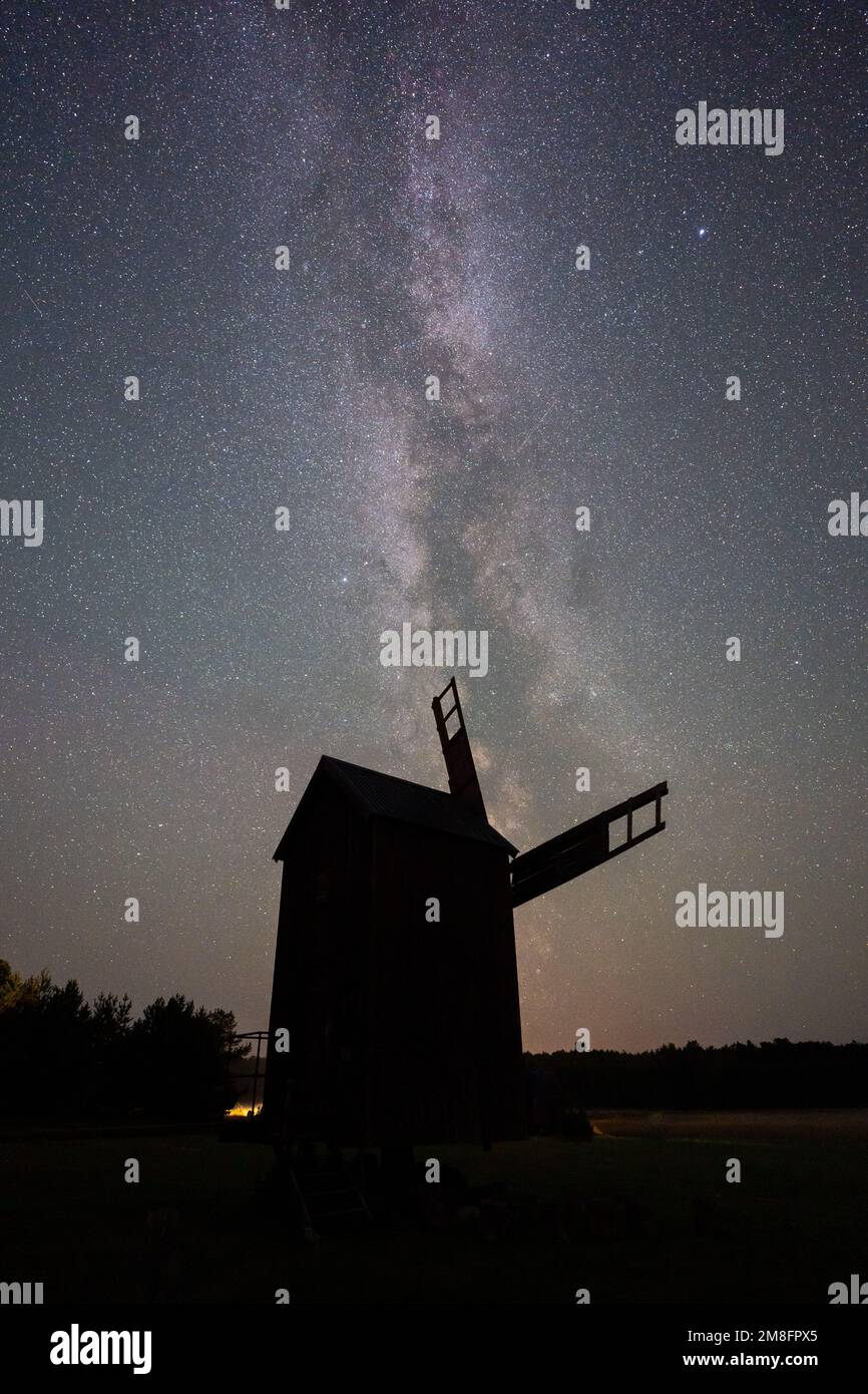A vertical shot of the silhouette of a windmill under the Milky Way constellation at night Stock ...