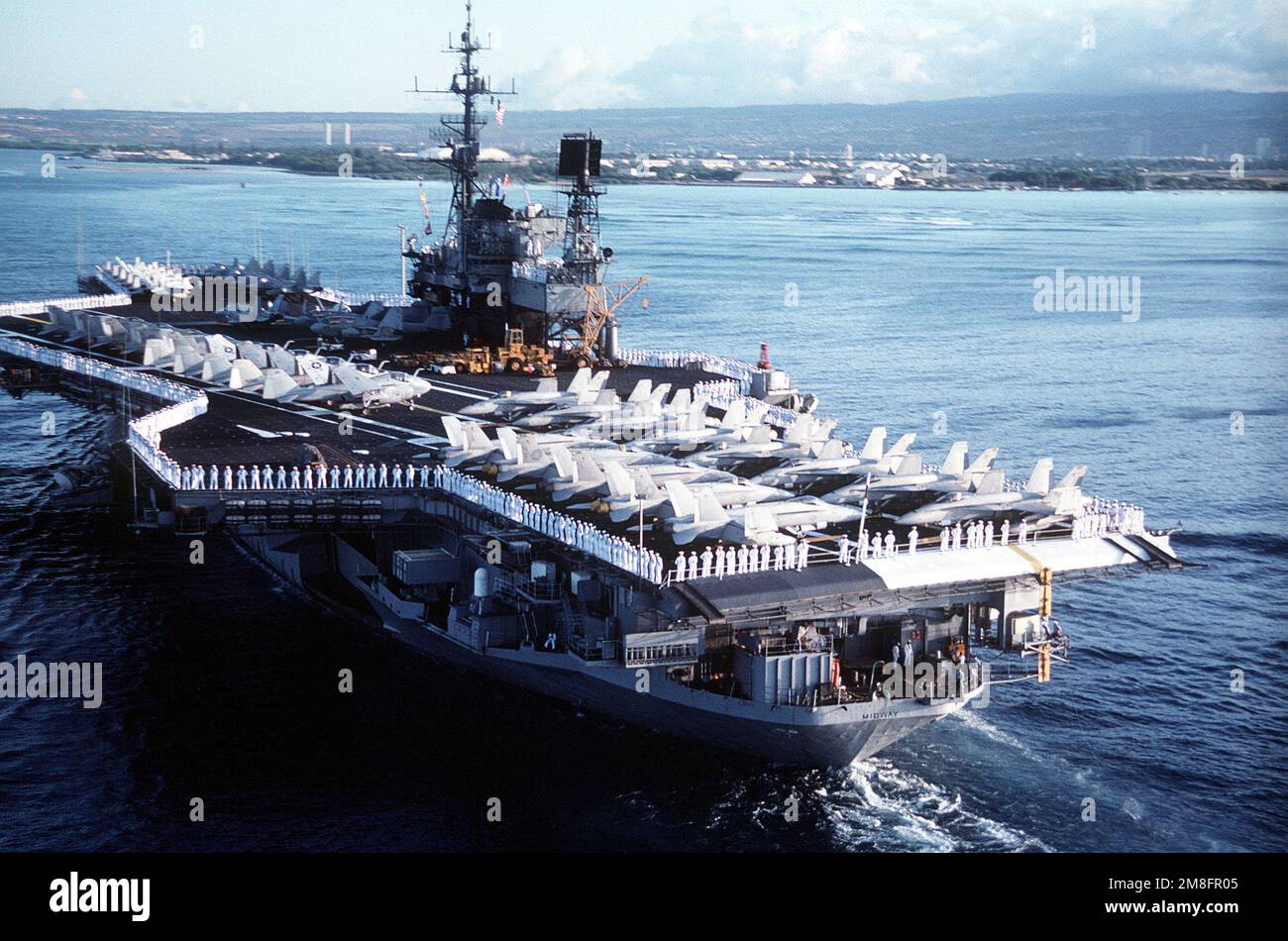 The crew of the aircraft carrier USS MIDWAY (CV-41) mans the rails as ...