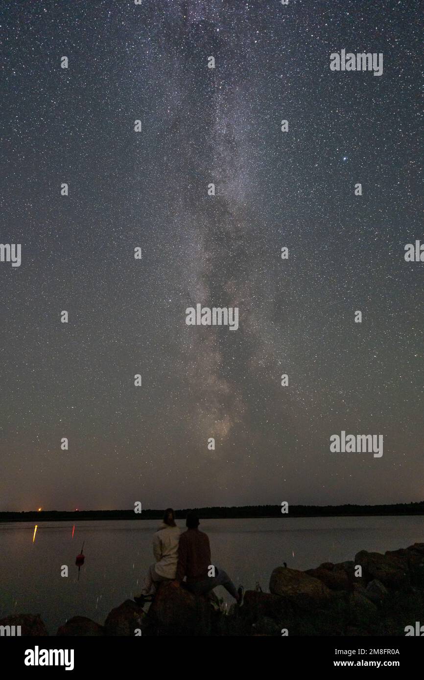 A vertical shot of a couple admiring the Milky Way constellation ...