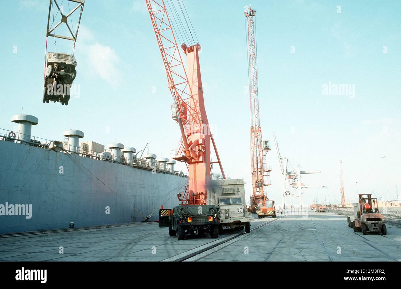 A crane on the pier is used to hoist a 5-ton cargo truck from the deck ...