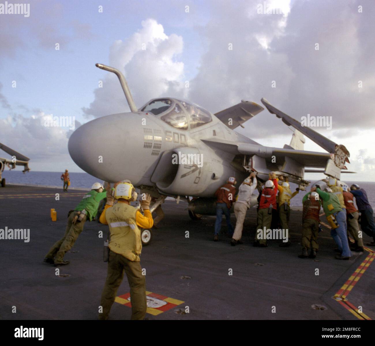 Flight deck crewmen position an Attack Squadron 75 (VA-75) A-6E ...