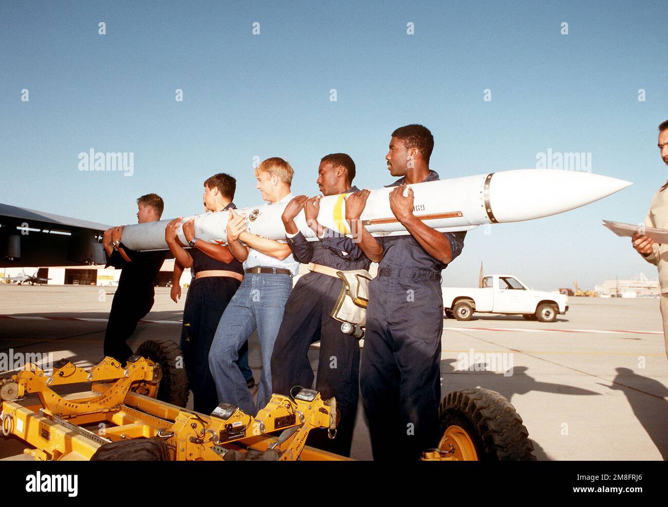 Aviation ordnancemen lift an AIM-7 Sparrow missile off of a weapons ...