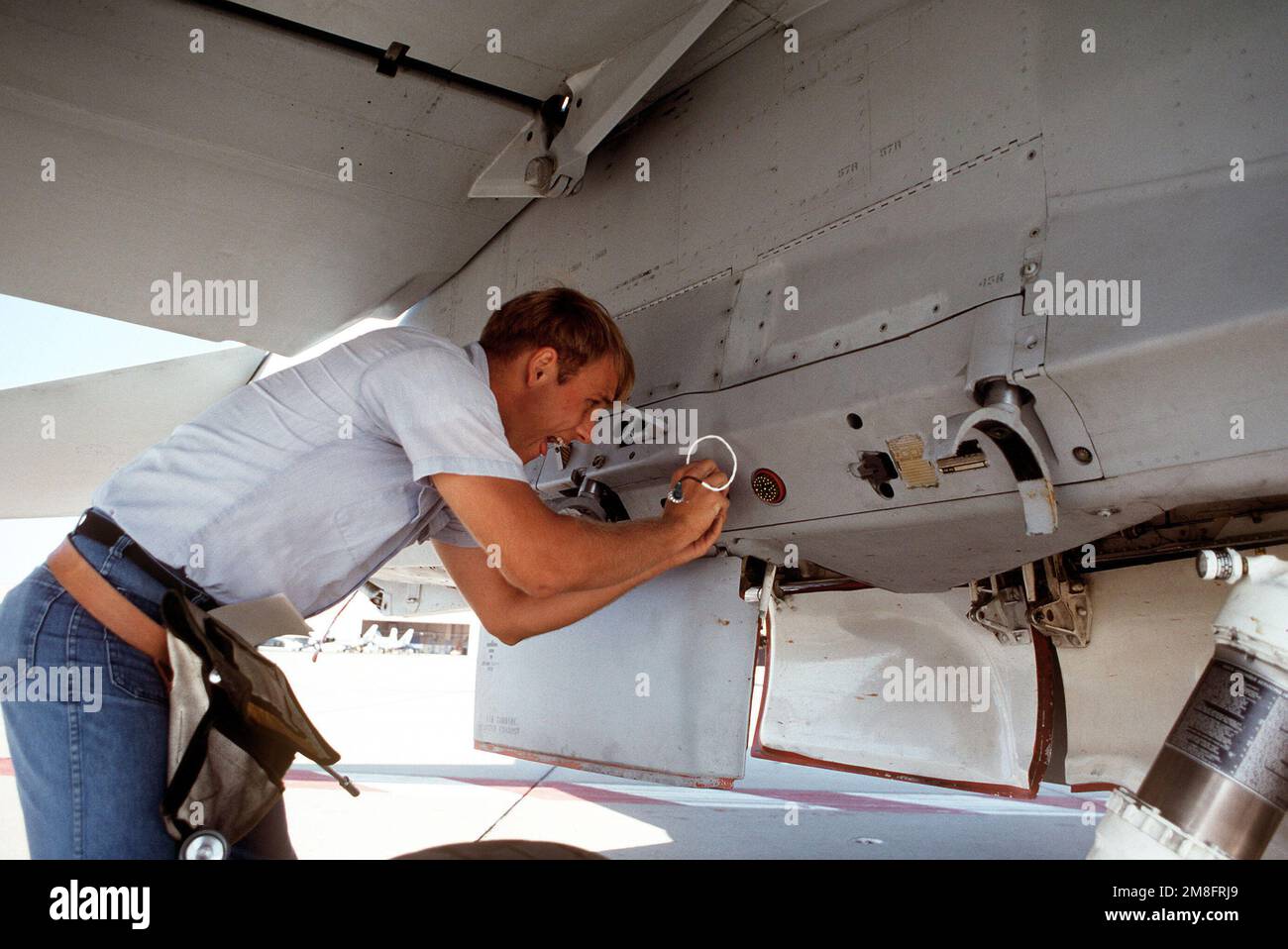 An aviation ordnancemn hooks up an electrical connection beneath the ...