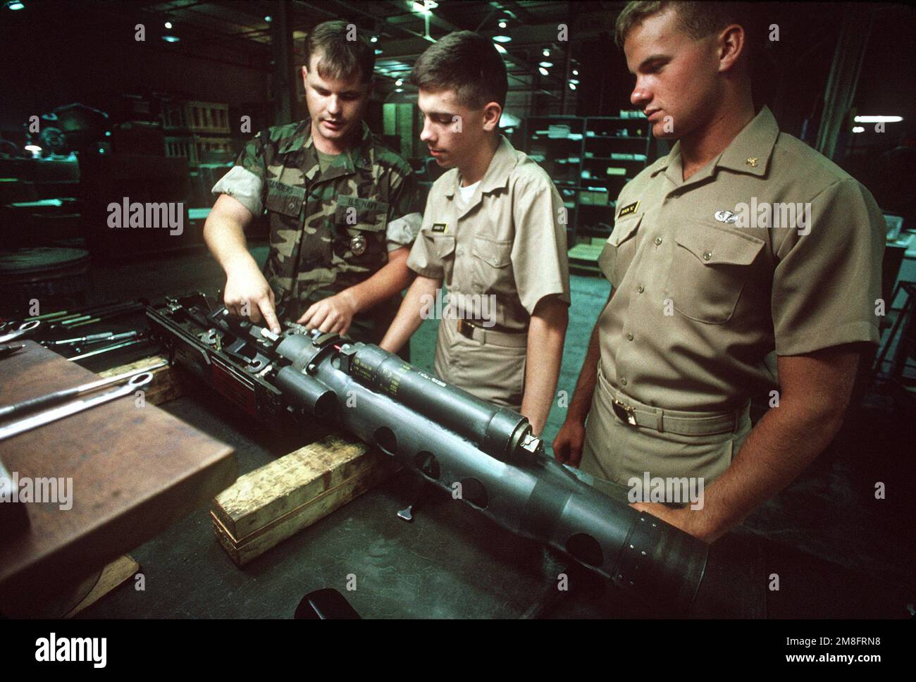 A petty officer points out a feature in the receiver of an M-242 Bushmaster 25mm chain gun to ...