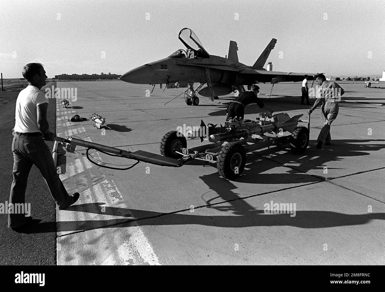 Aviation ordnancemen move a weapons skid into place near a Strike ...