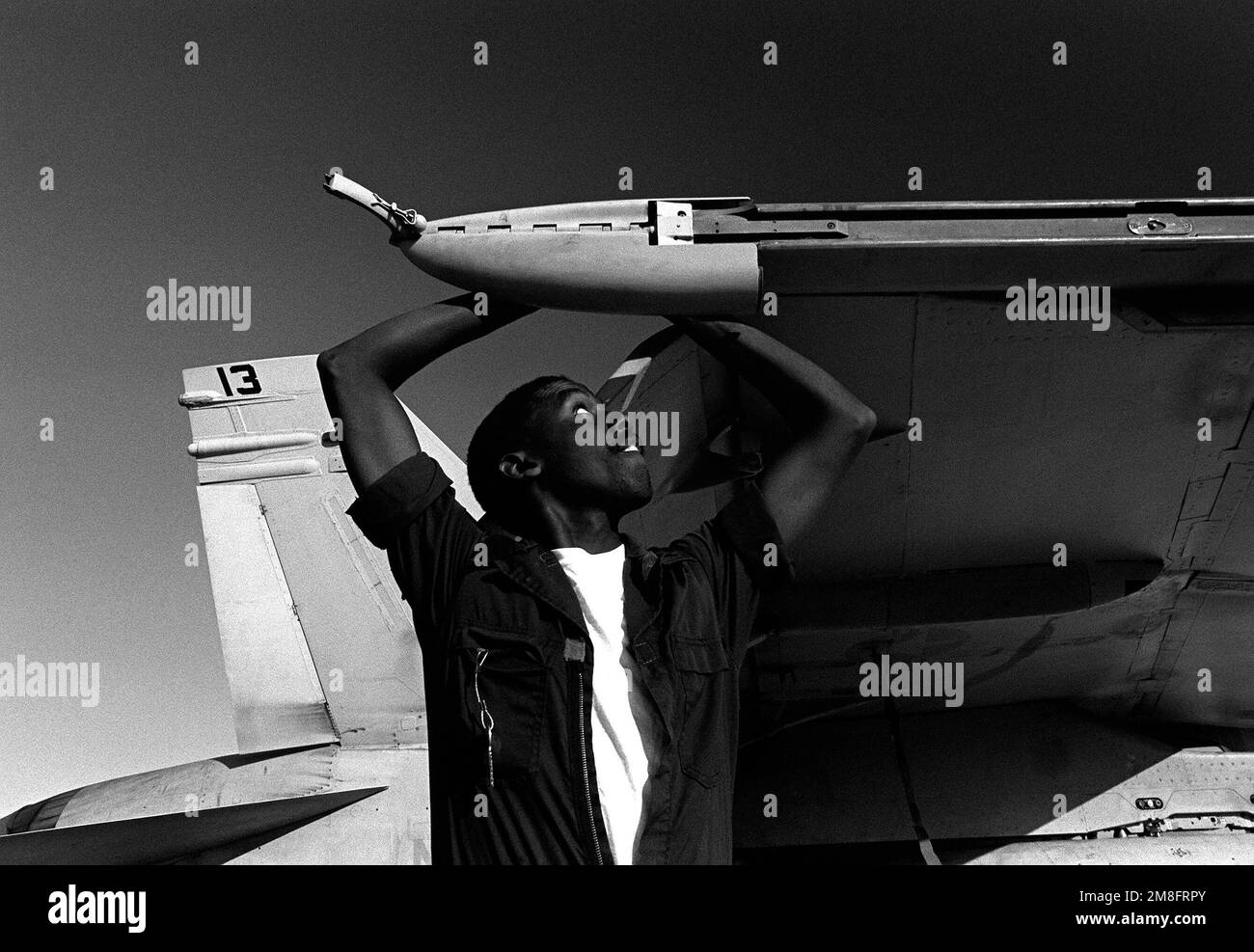 An aviation ordnancemen works on the launch rail at the end of the ...