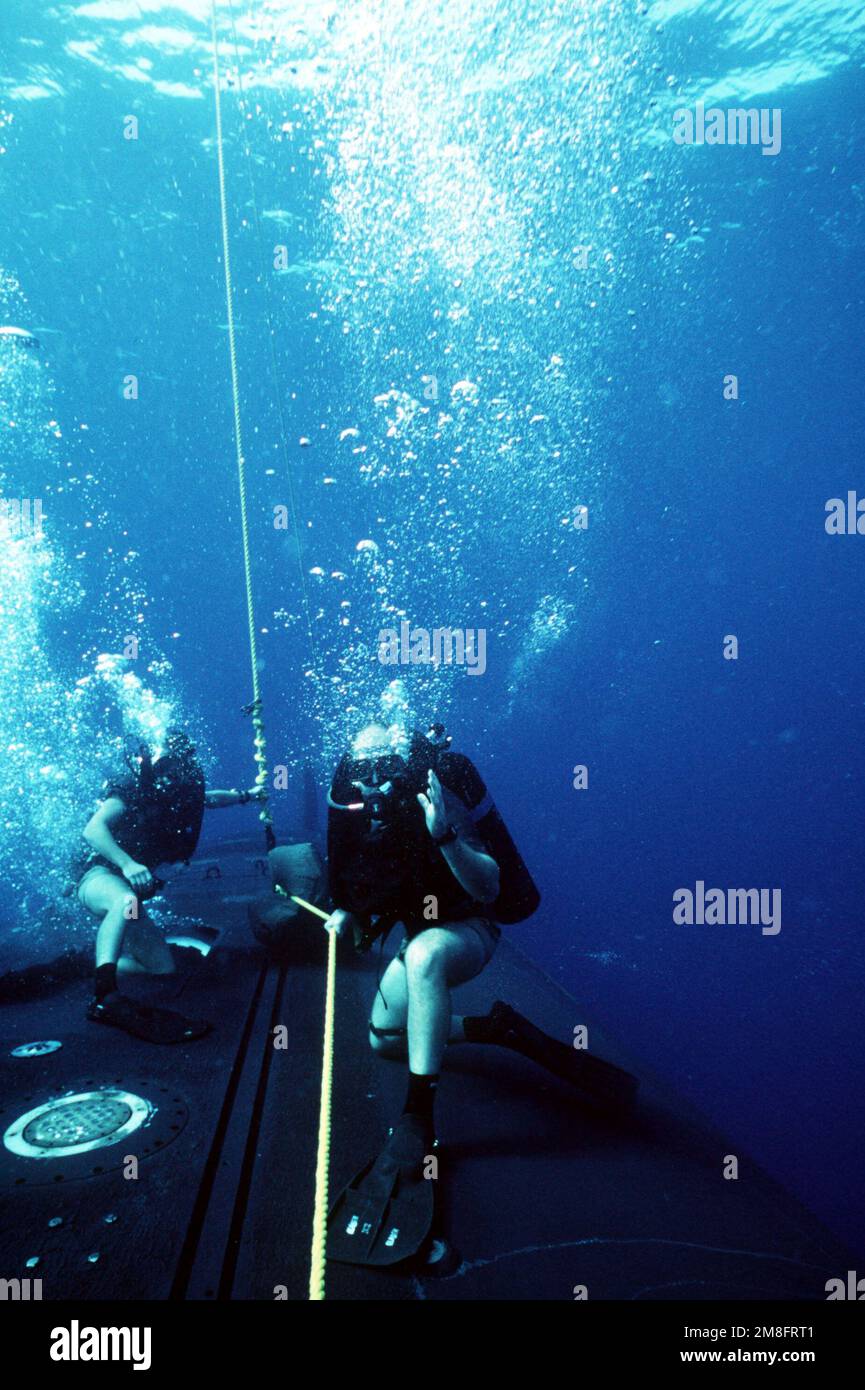 Members of Navy sea-air-land (SEAL) team rig lines on the hull of a ...