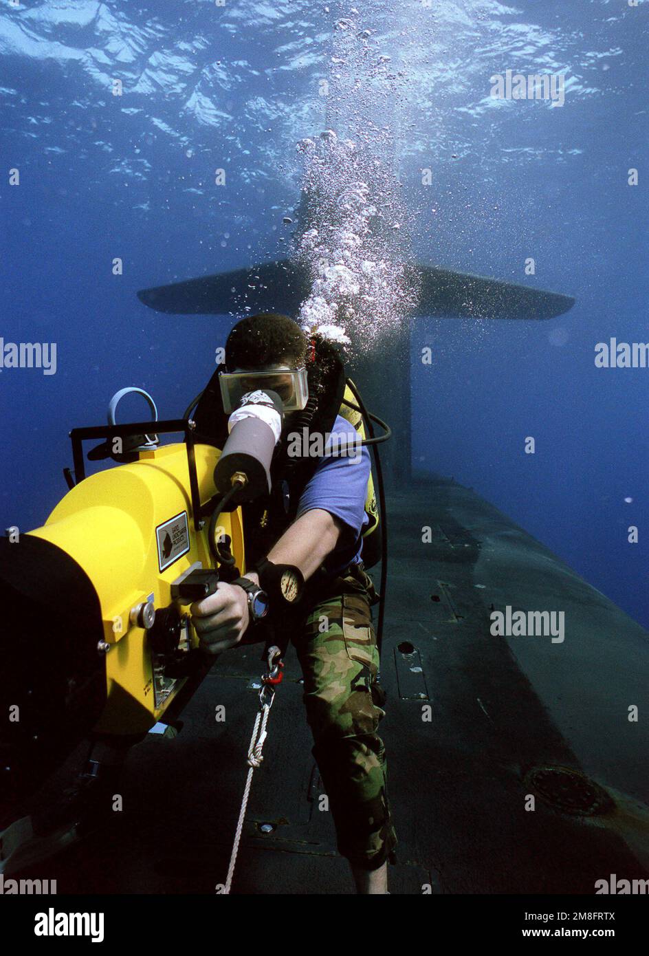 A photographer's mate/diver aims his video camera at a hatch in the ...