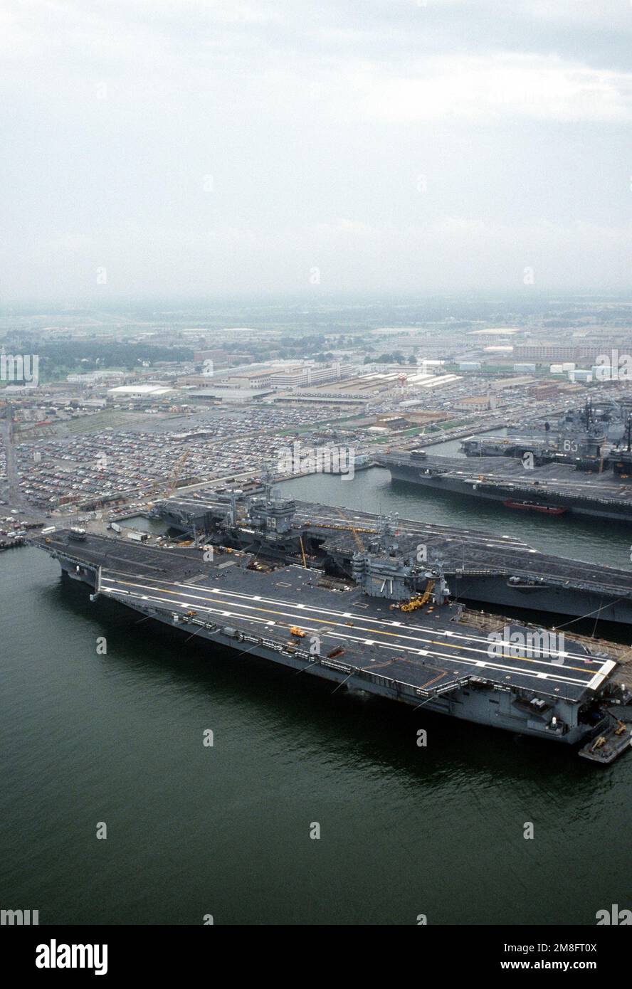 The nuclear-powered aircraft carrier USS THEODORE ROOSEVELT (CVN-71), foreground, lies tied up ...