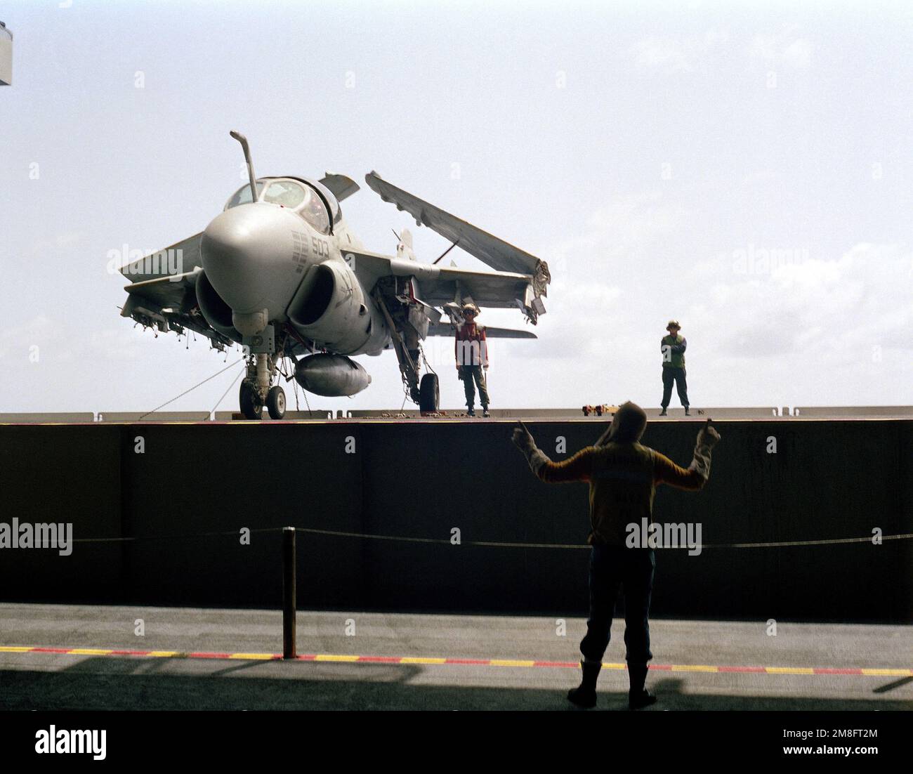 A crew member on an elevator signals to flight deck crew members as ...
