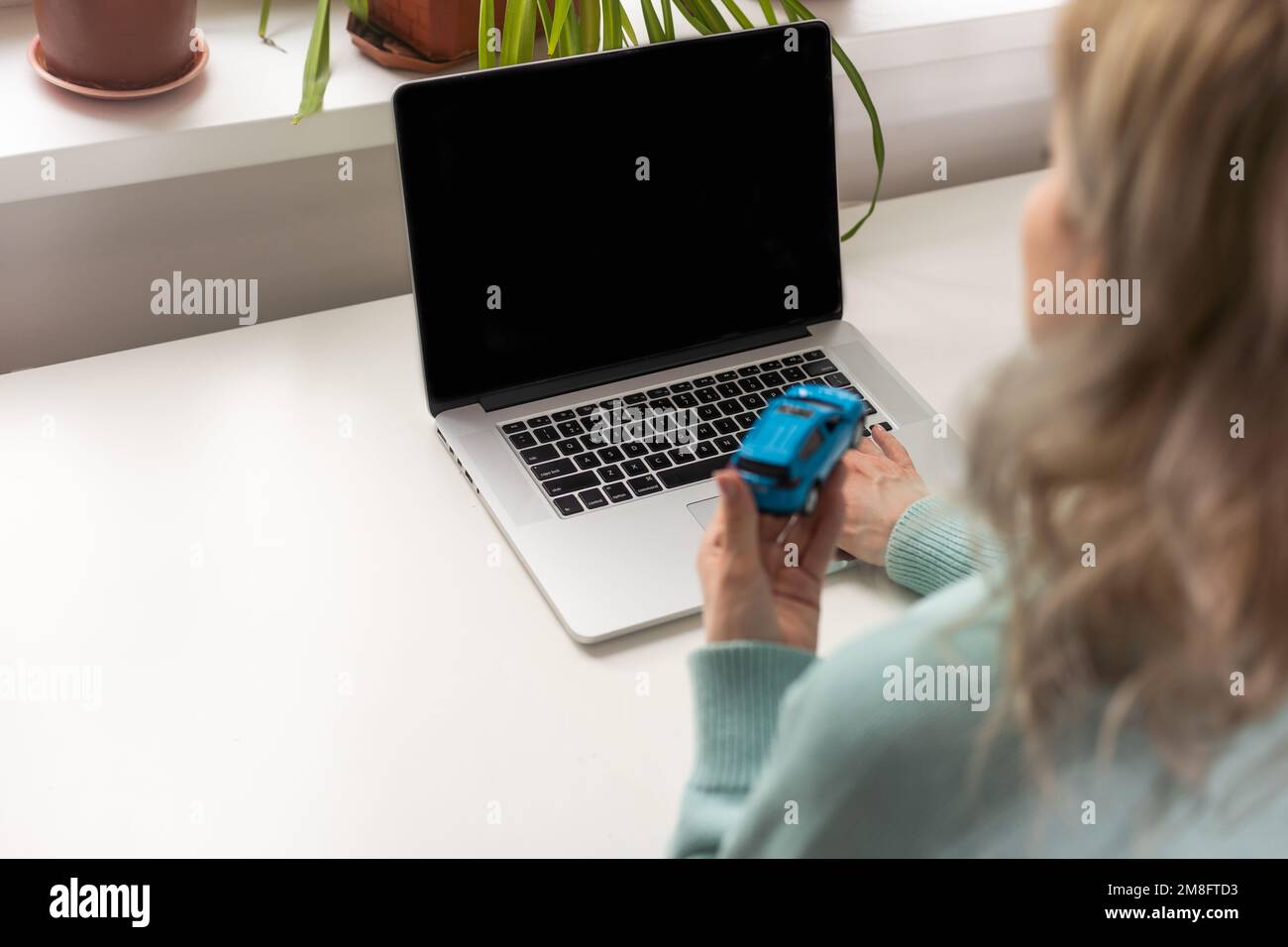 hands of a woman on a desk behind a keyboard with a small model car ...