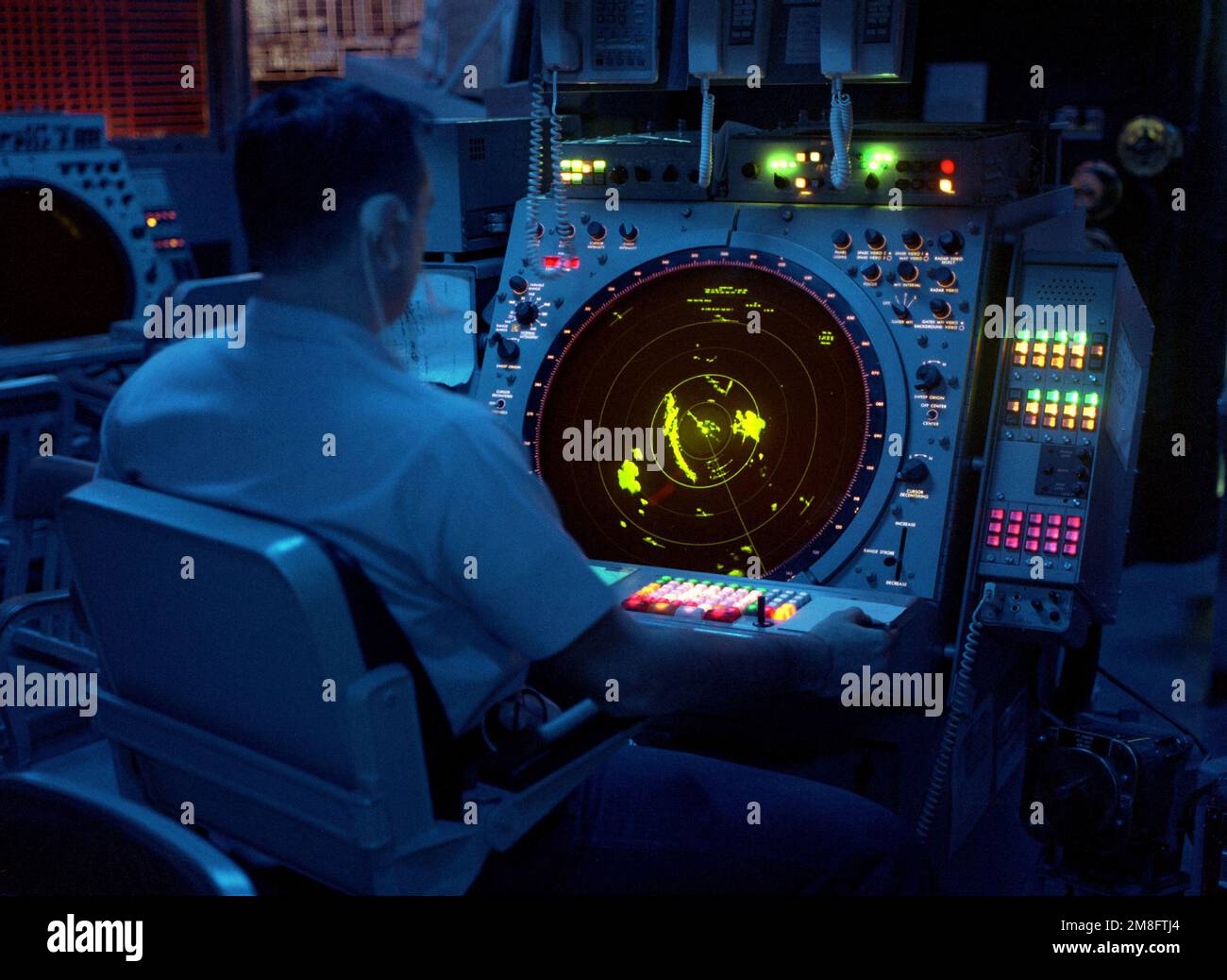 A crewman mans an air operations radar console in the combat direction ...