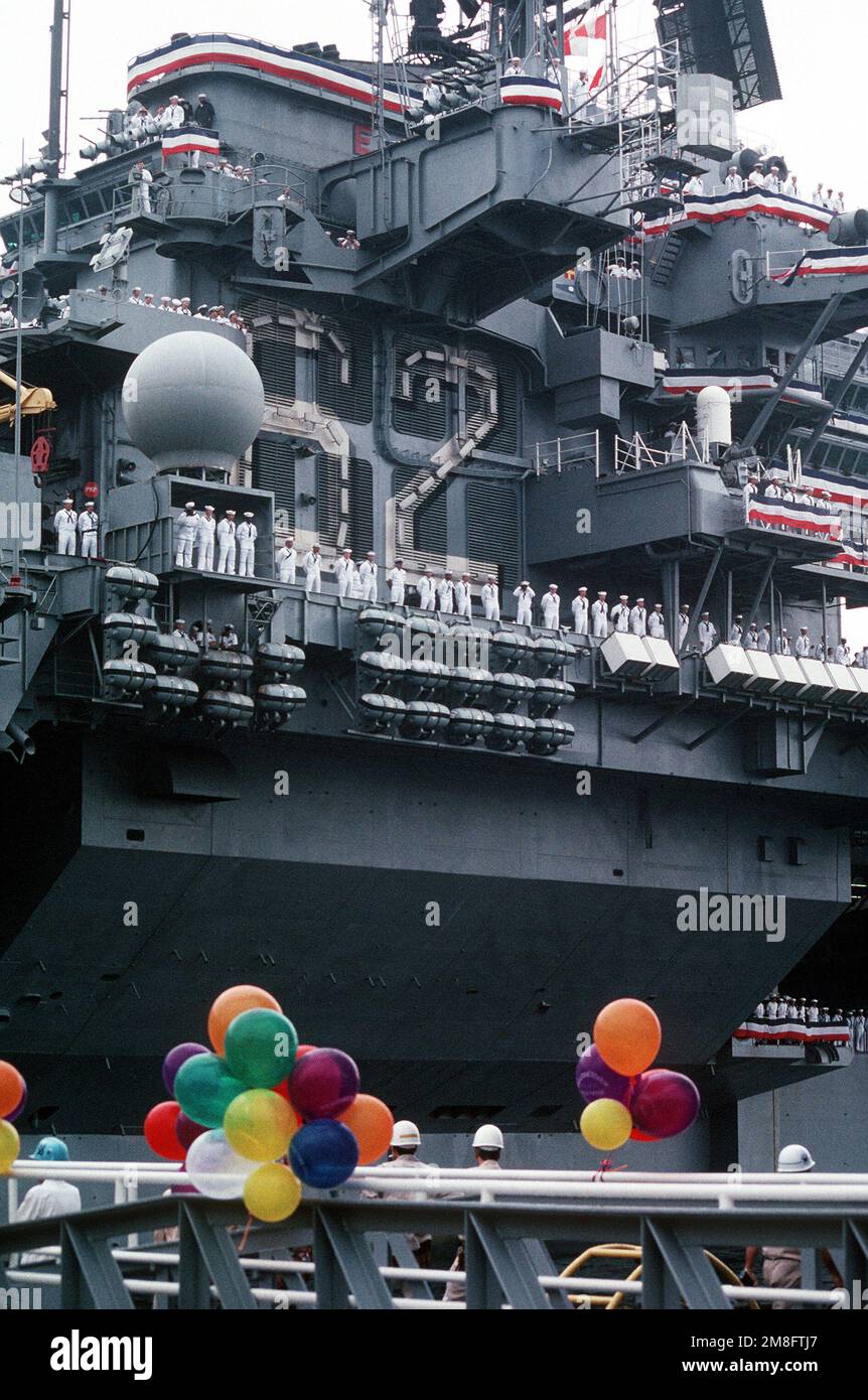 Crew members man the rails near the island aboard the aircraft carrier ...