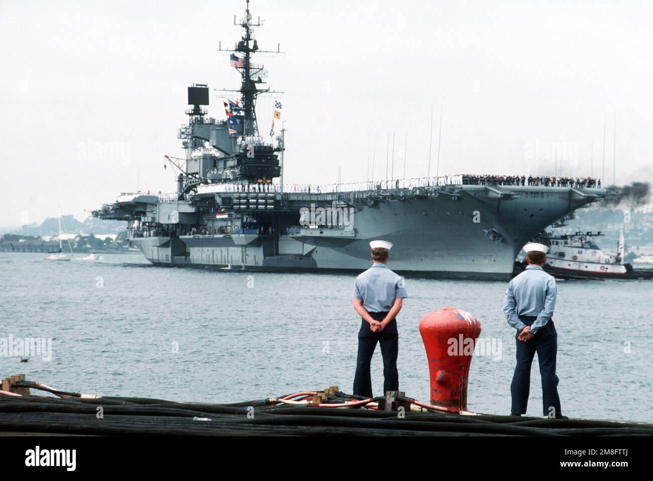 Line handlers stand by as a tug boat helps maneuver the aircraft ...