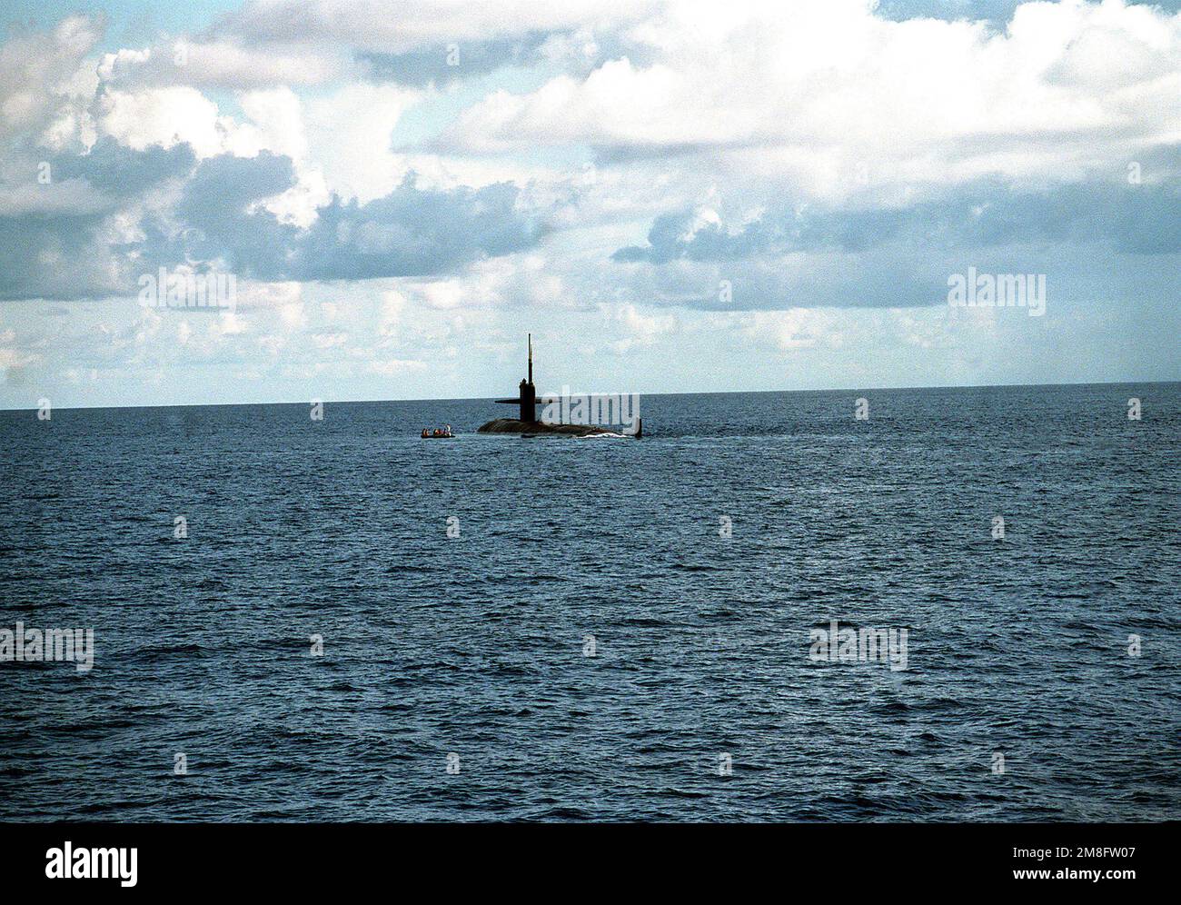 An inflatable boat floats near the nuclear-powered attack submarine USS ...