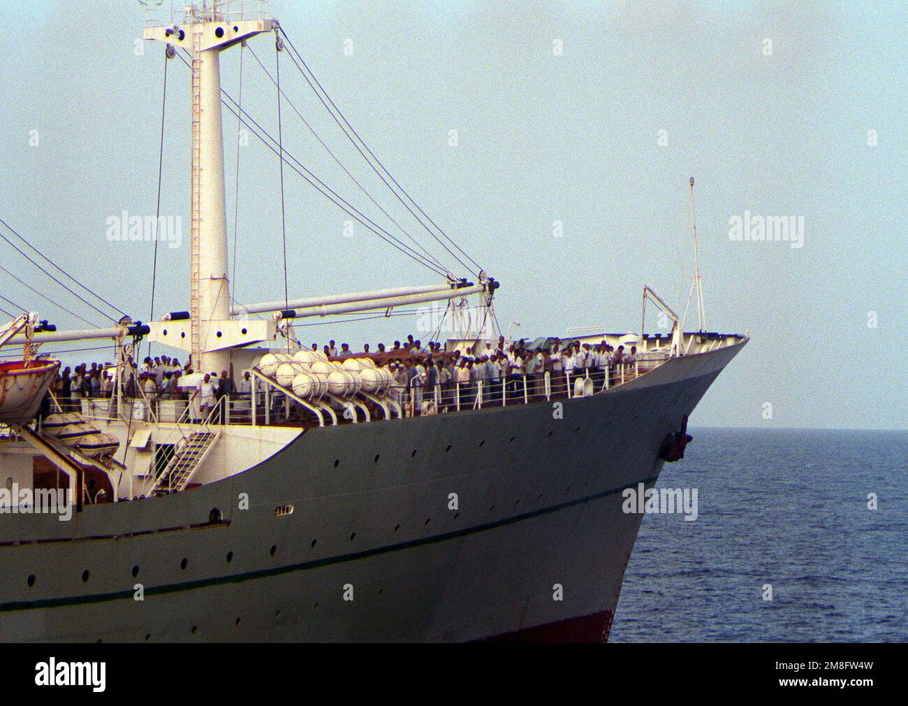 Crew members and passengers wait near the bow of the Indian passenger ...
