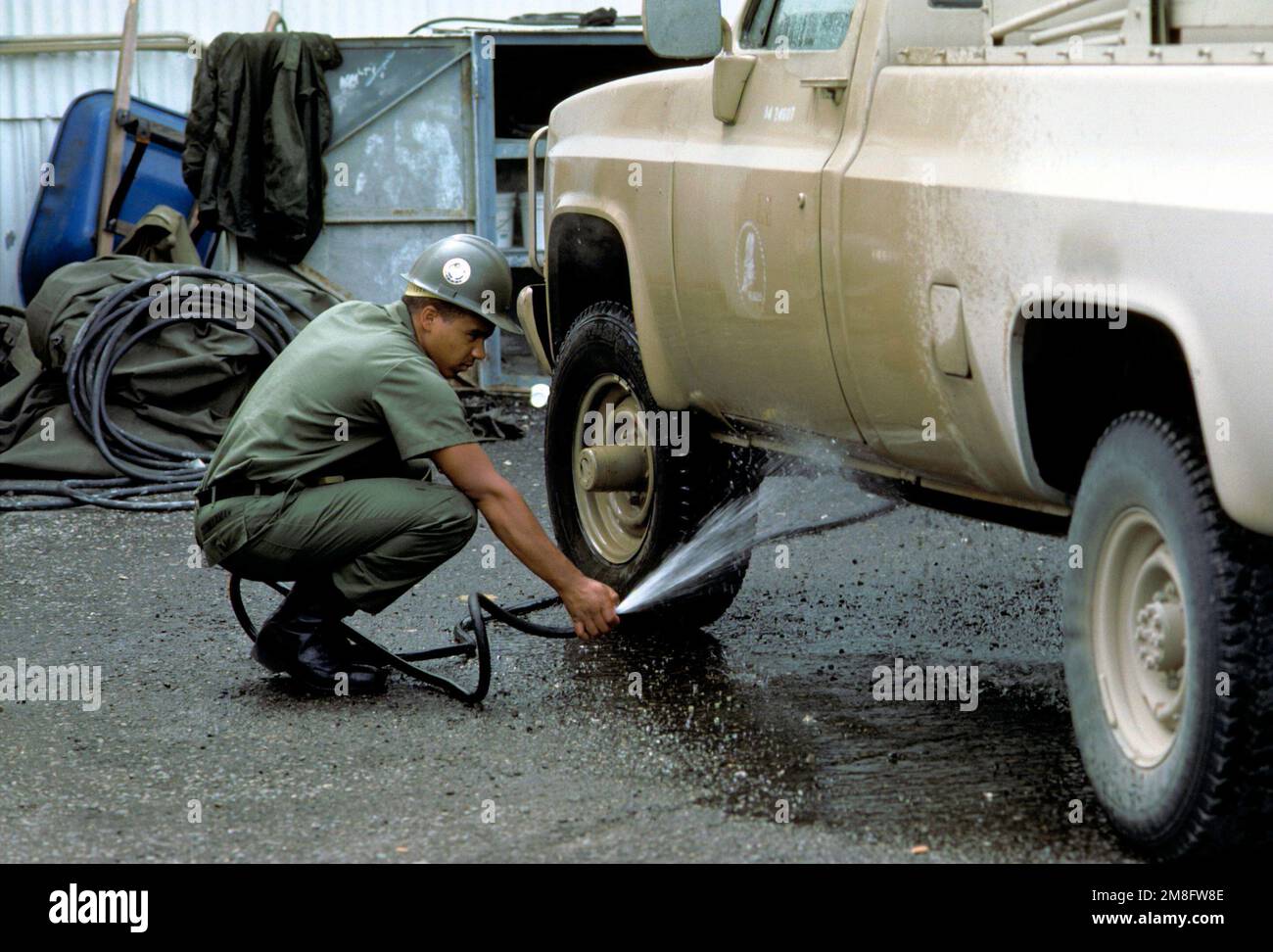 A Seabee from Naval Mobile Construction Battalion 4 (NMCB-4) hoses off ...