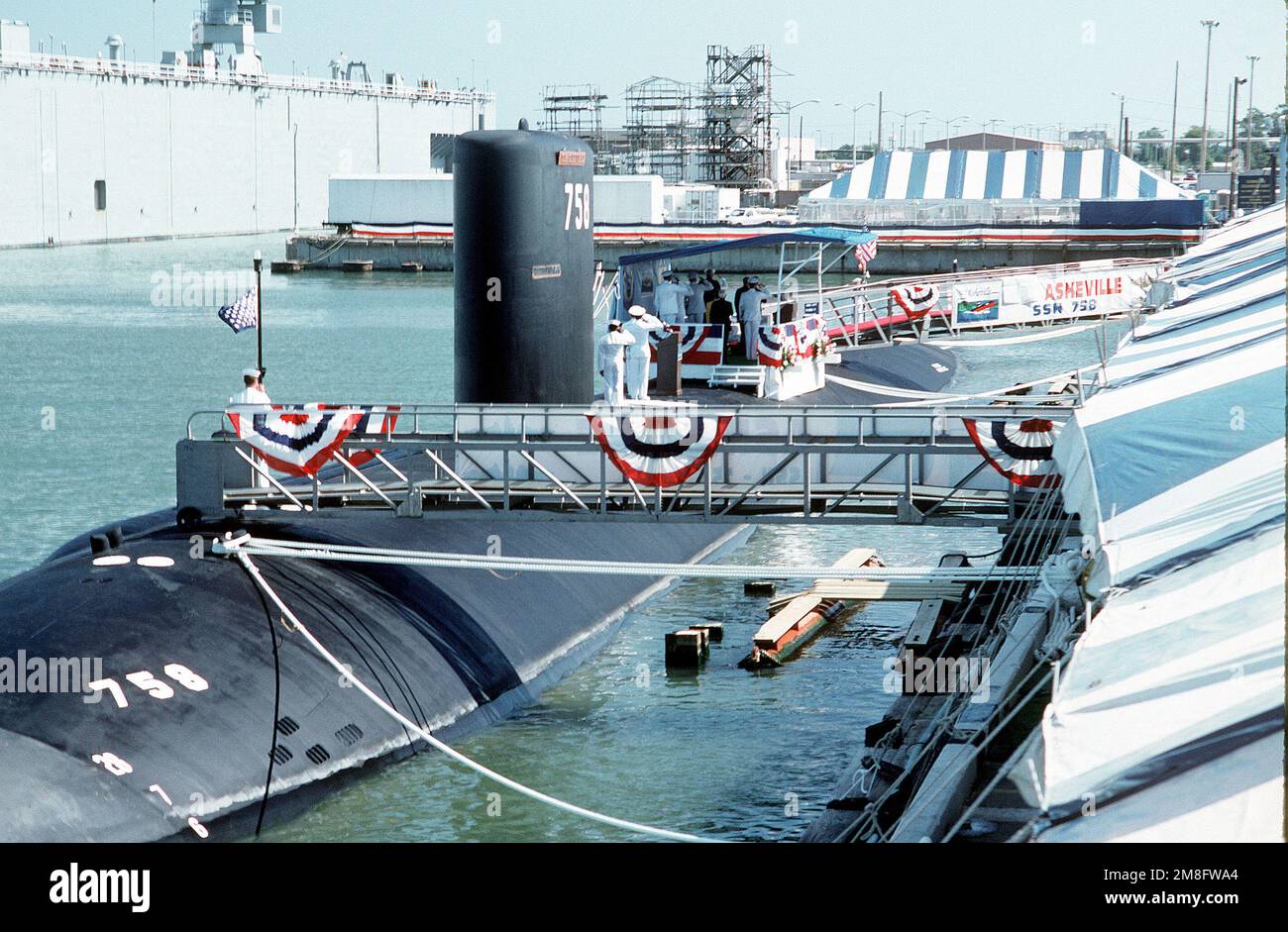 Crew members and guests salute as the colors are raised at the stern of ...