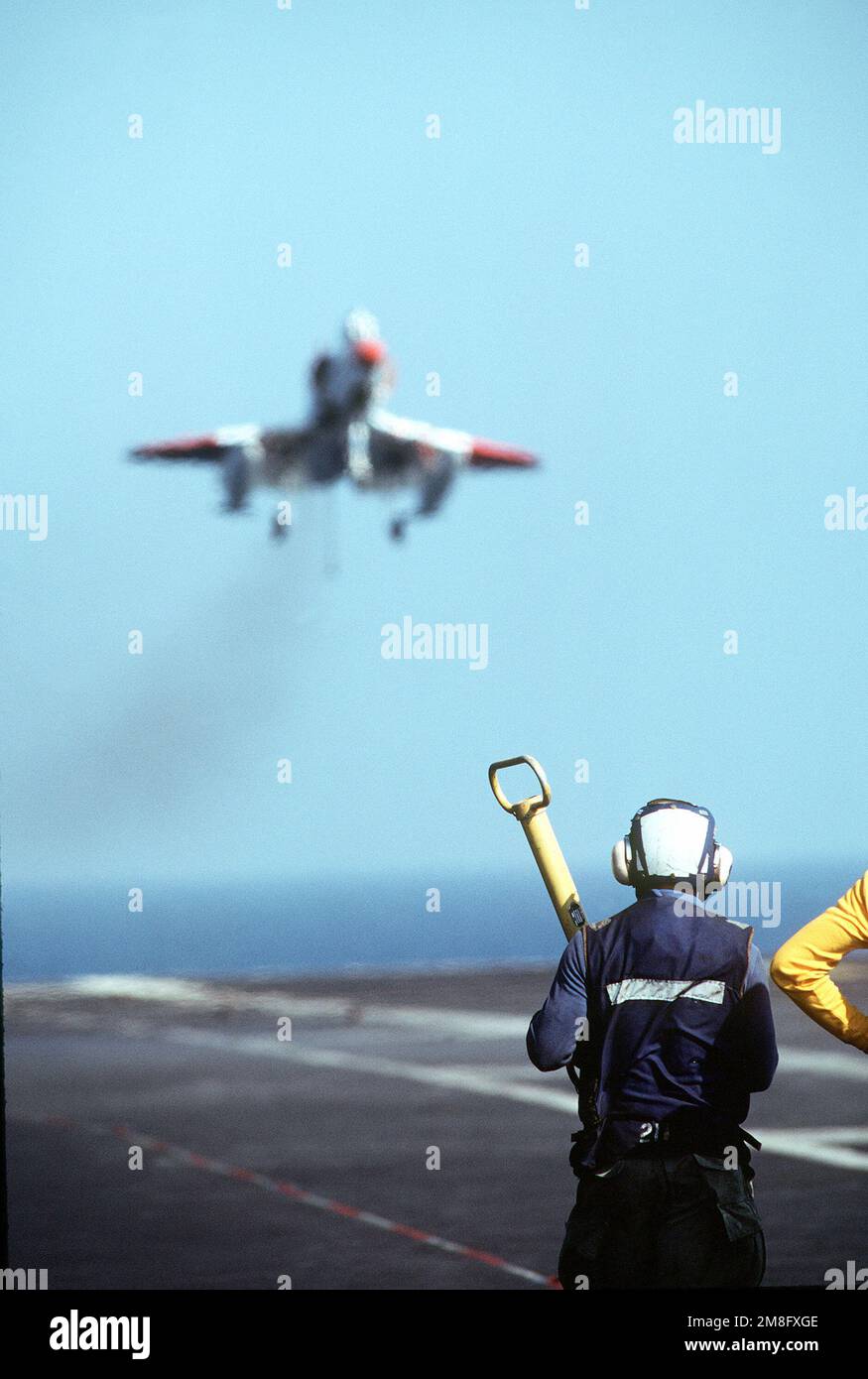 An aircraft handler stands by with a tiller bar on the flight deck of ...