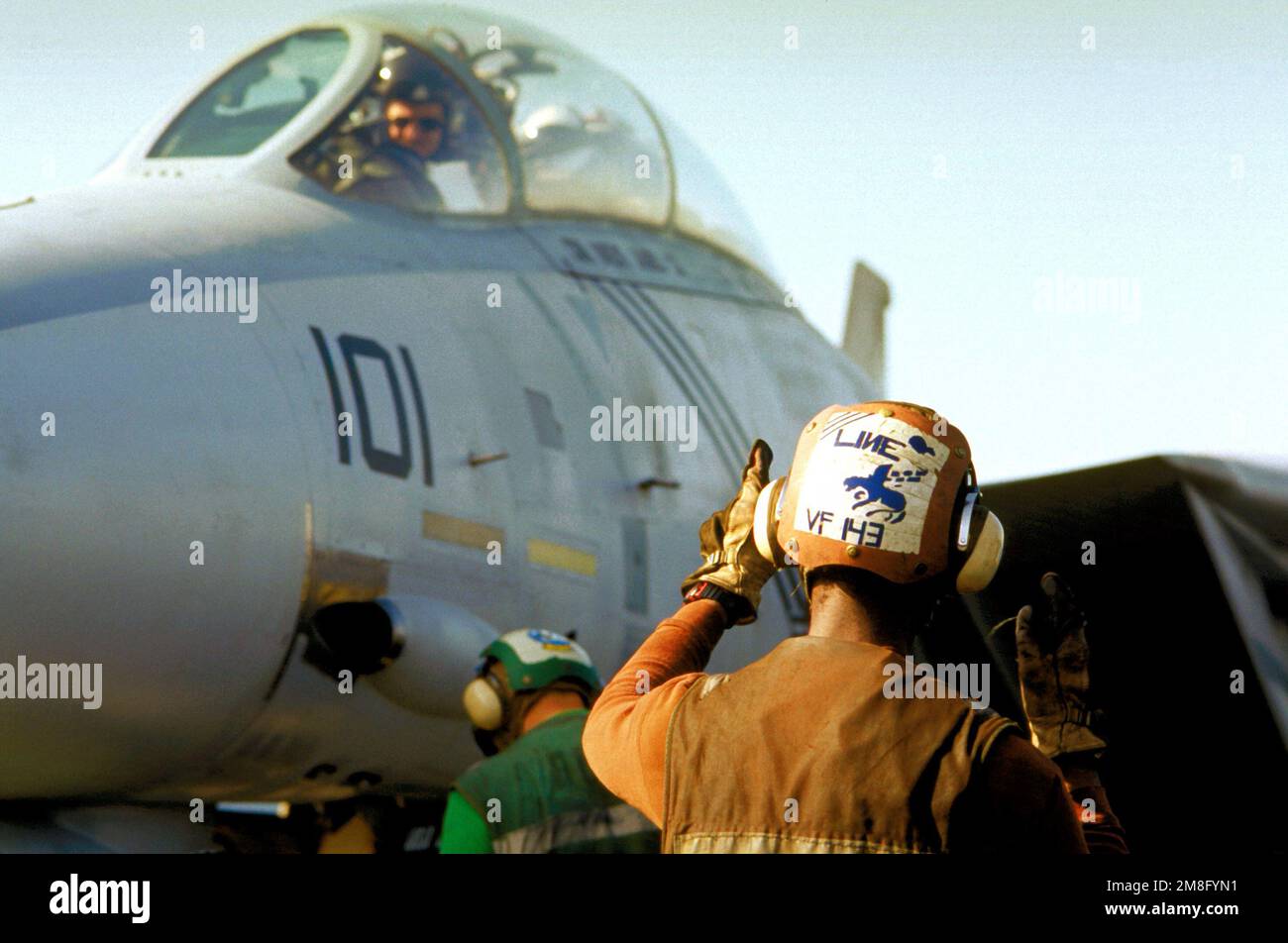 A plane captain signals to the pilot of a Fighter Squadron 143 (VF-143) F-14B Tomcat aircraft as ...