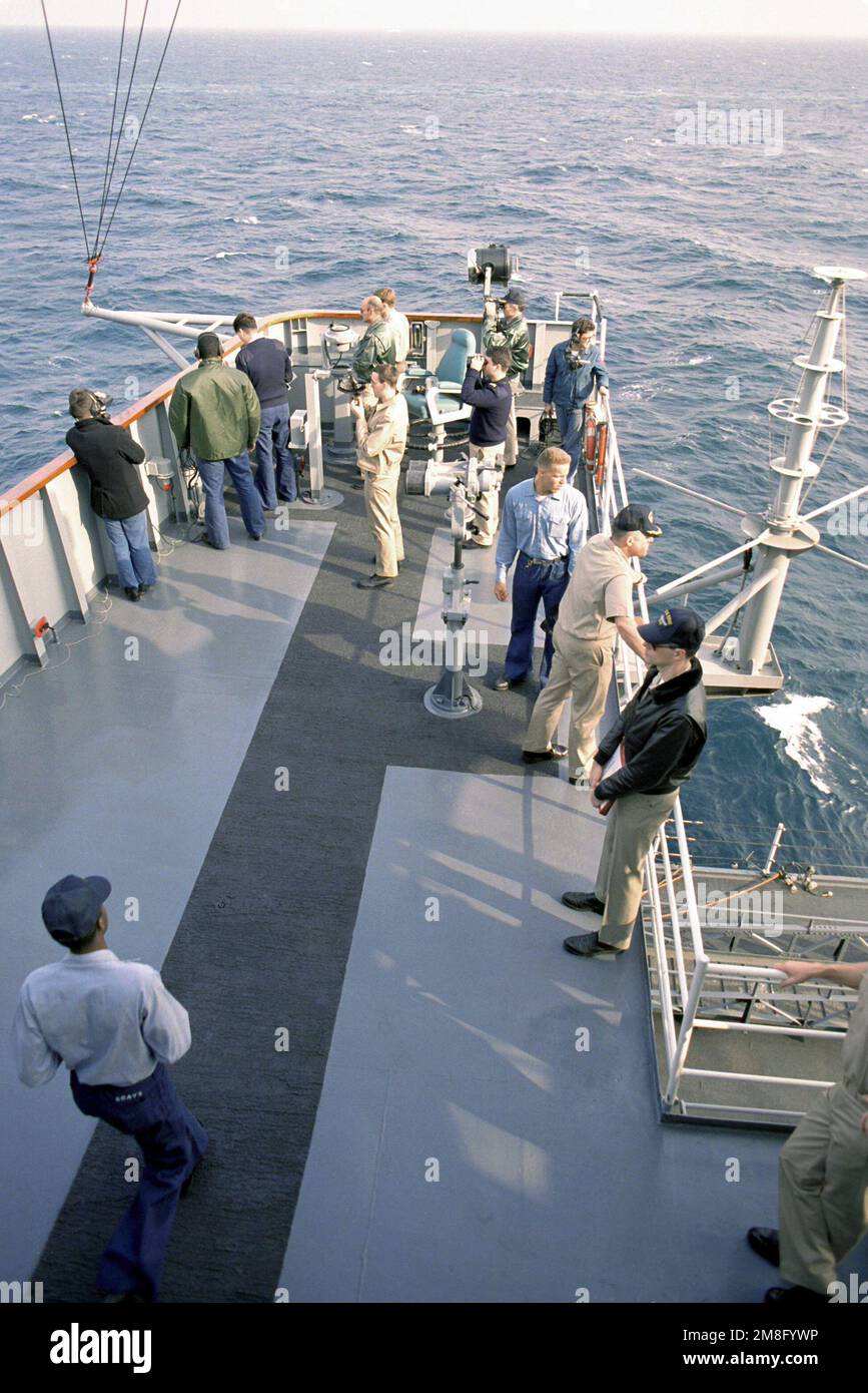 Officers and enlisted men watch from a bridge wing aboard the ...