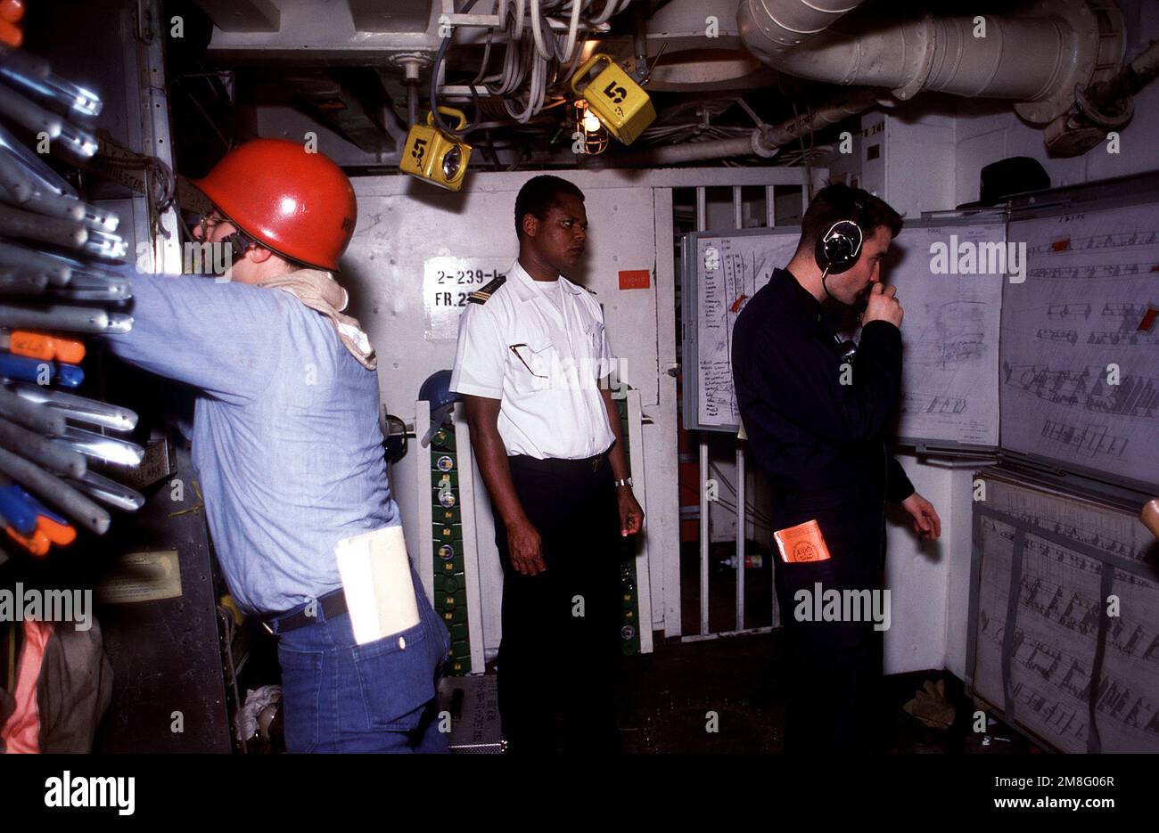 A West African officer watches as two petty officers work in a repair ...