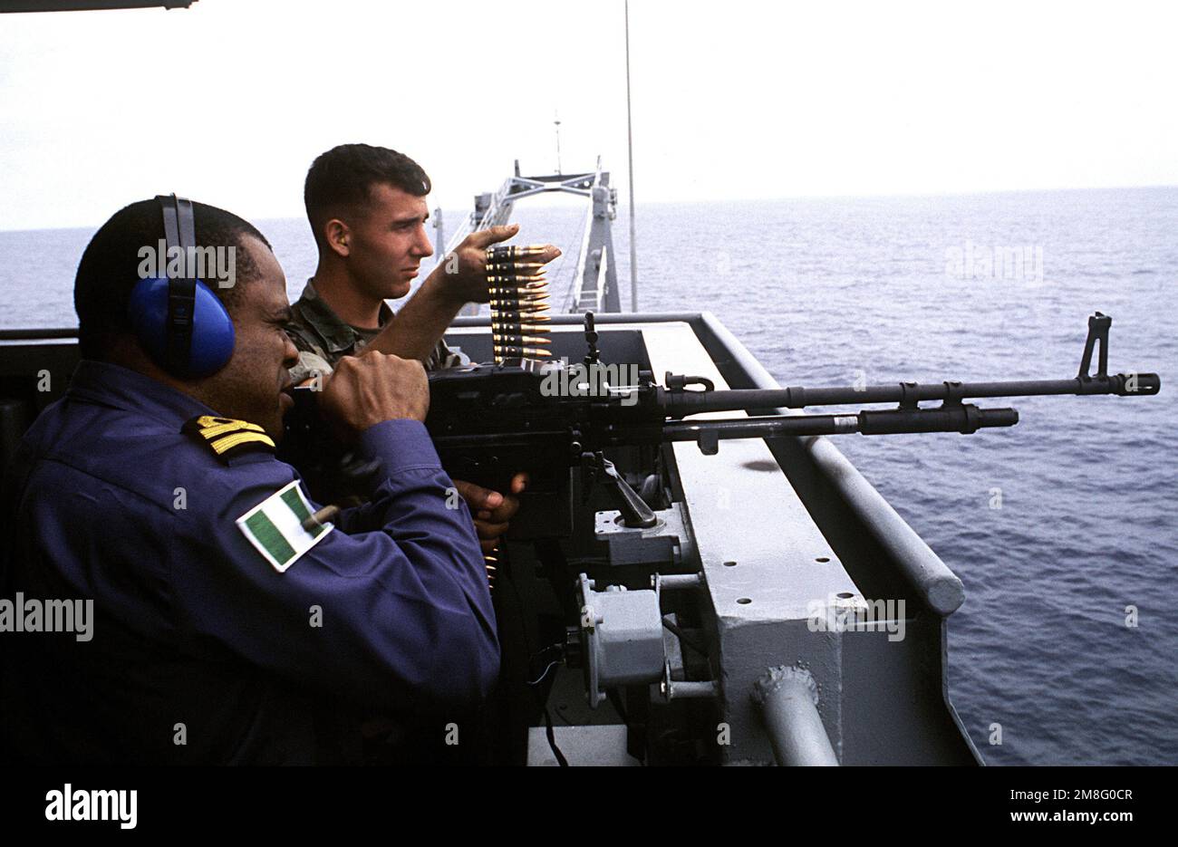 A Marine lance corporal feeds the ammunition as a Nigerian officer ...