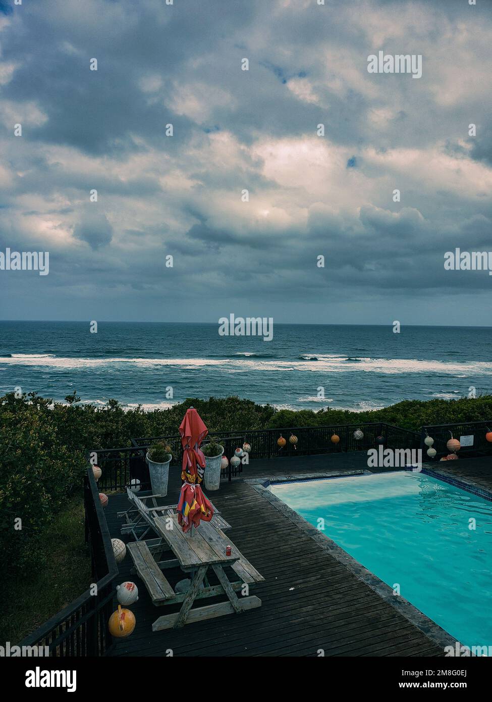 A vertical shot of a private pool with a seascape under cloudy sky ...