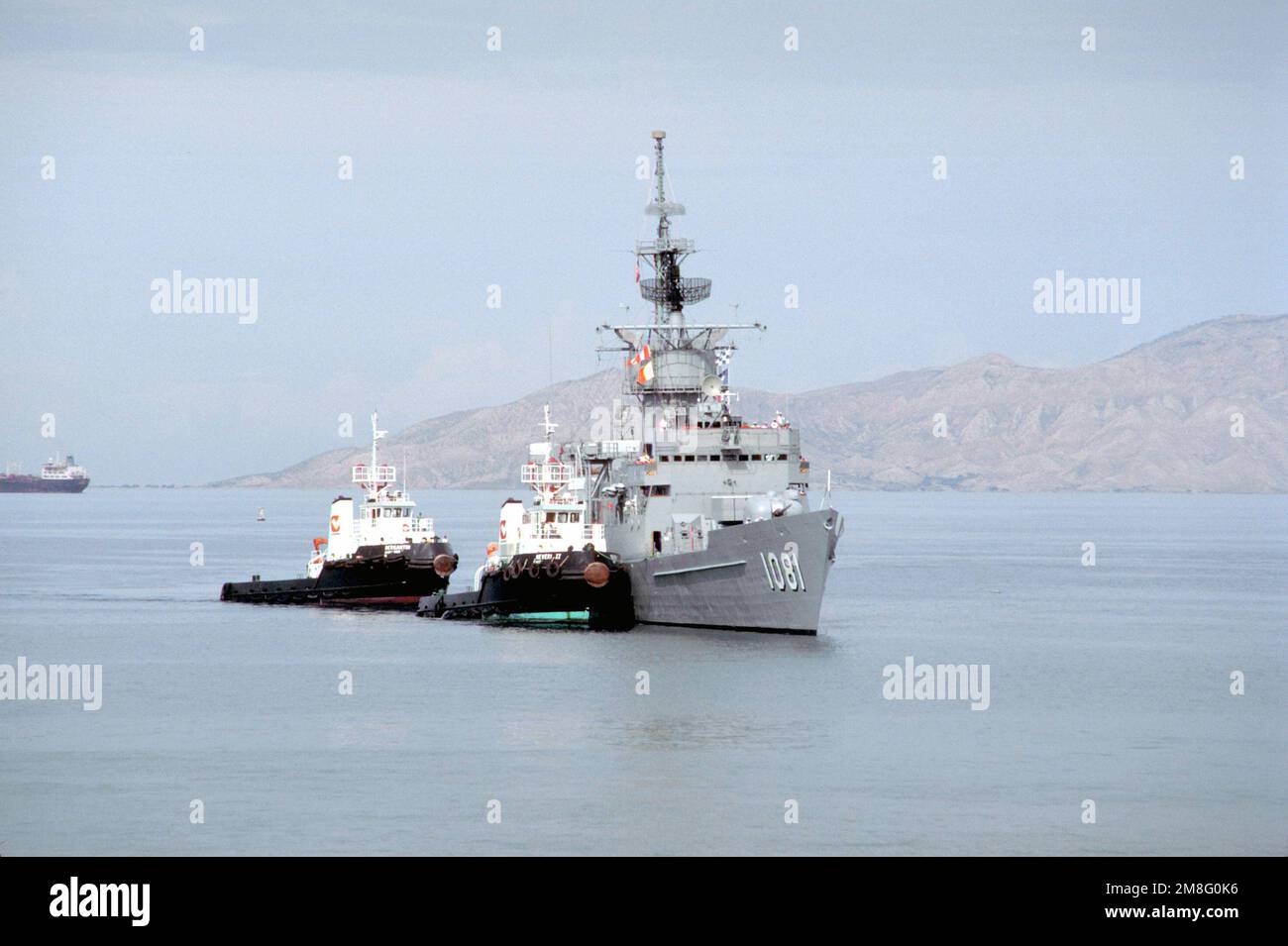 Two tug boats come alongside the frigate USS AYLWIN (FF-1081) to assist ...