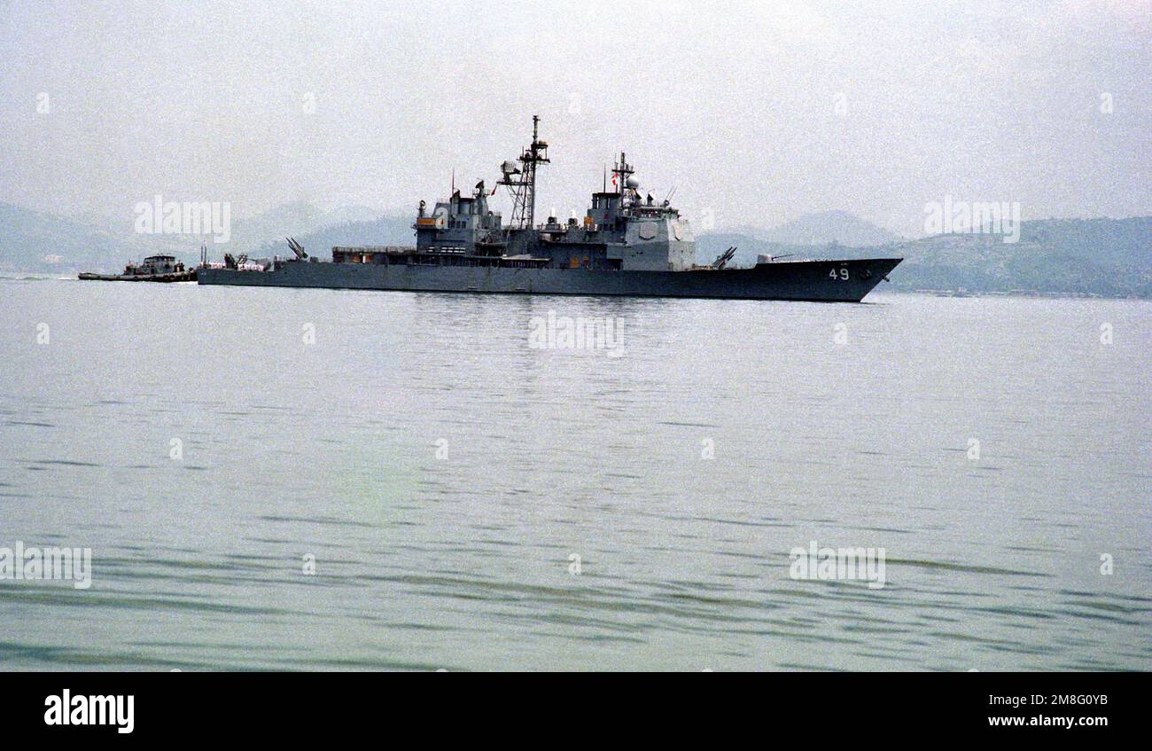 A harbor tug follows the guided missile cruiser USS VINCENNES (CG-49 ...