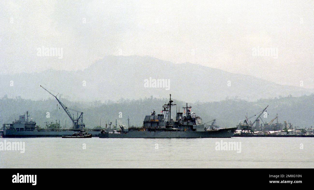 A harbor tug follows the guided missile cruiser USS VINCENNES (CG-49 ...