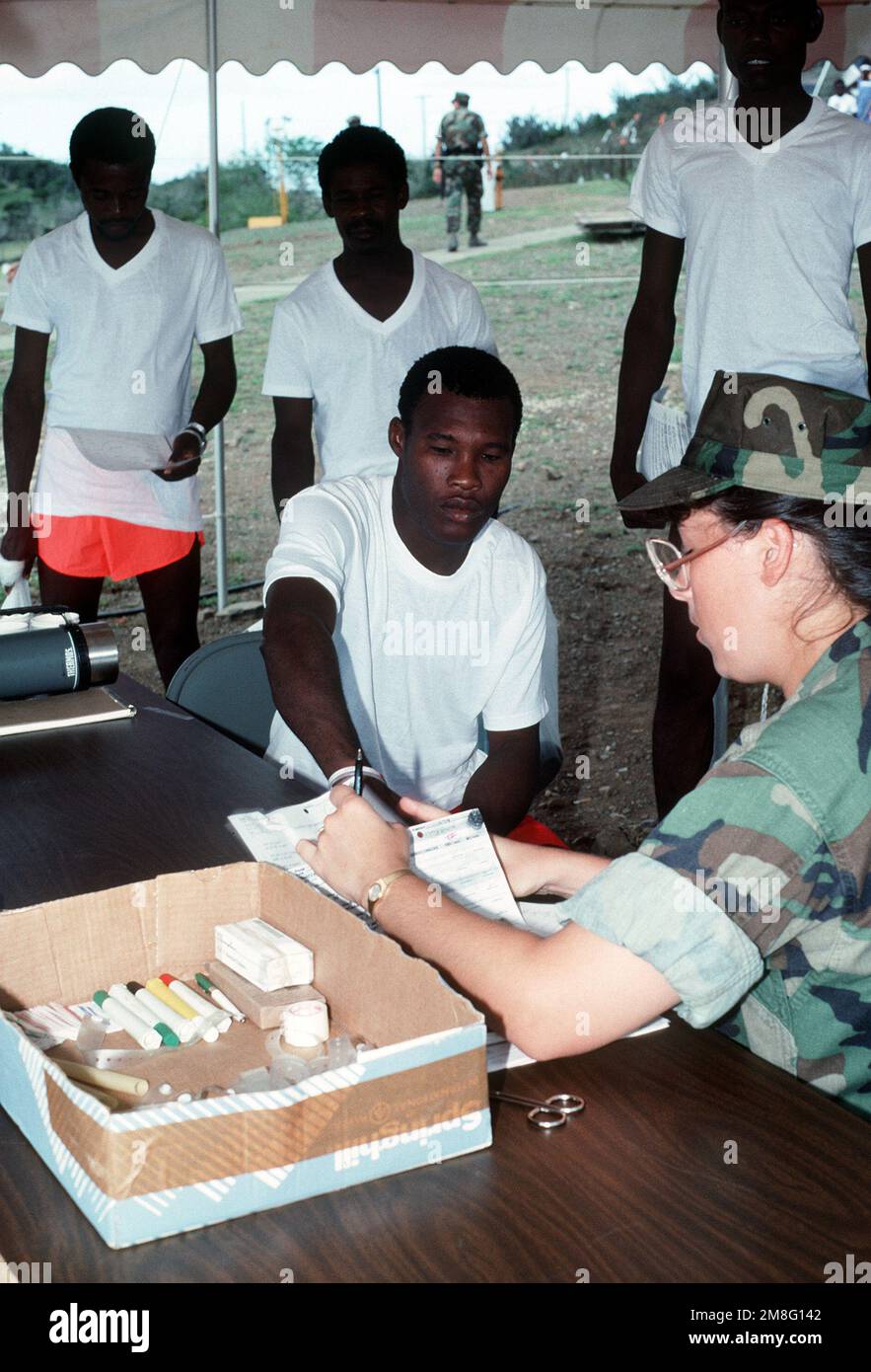 A woman Marine processes paperwork for Haitian refugees at Camp McCalla ...