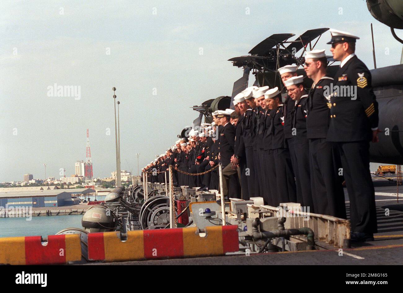 Crew members man the rails aboard the amphibious assault ship USS ...