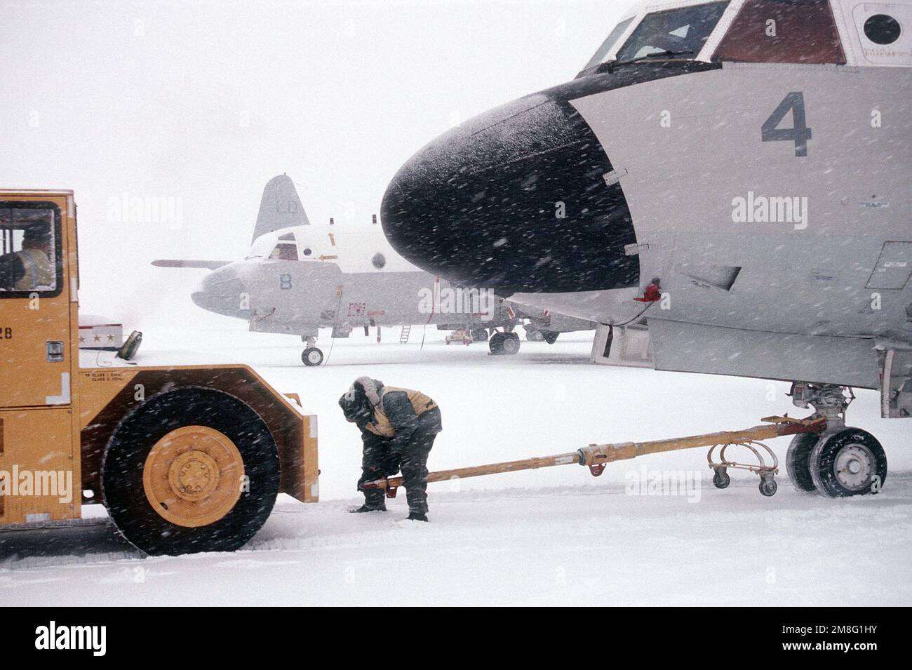 Crewmen position a tractor to tow a P-3 Orion anti-submarine aircraft ...