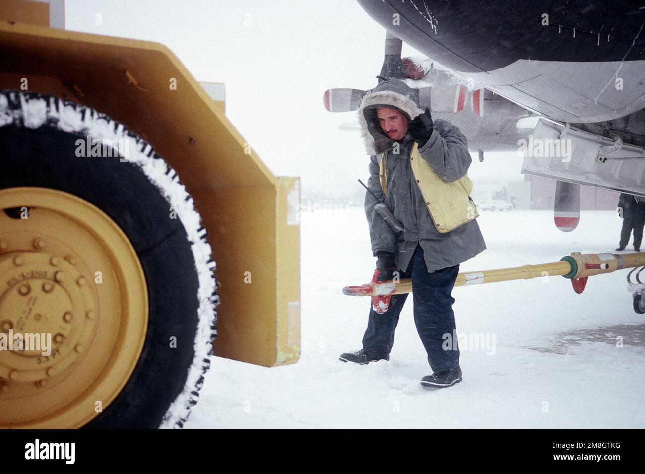 A crewman guides a tractor into position to tow a P-3 Orion anti ...