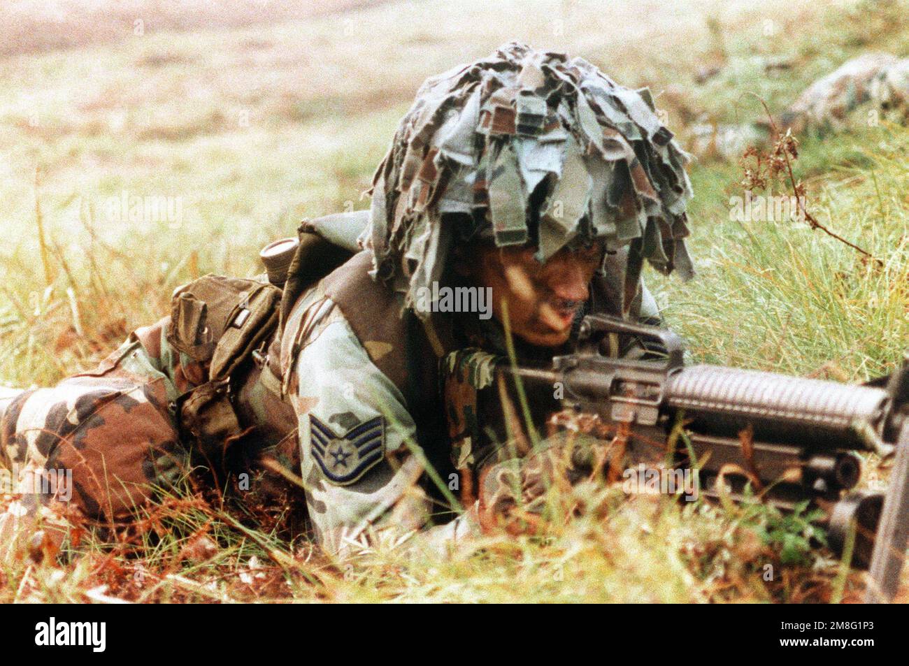 A US Air Force Security Policeman, in camouflage make-up, takes up ...
