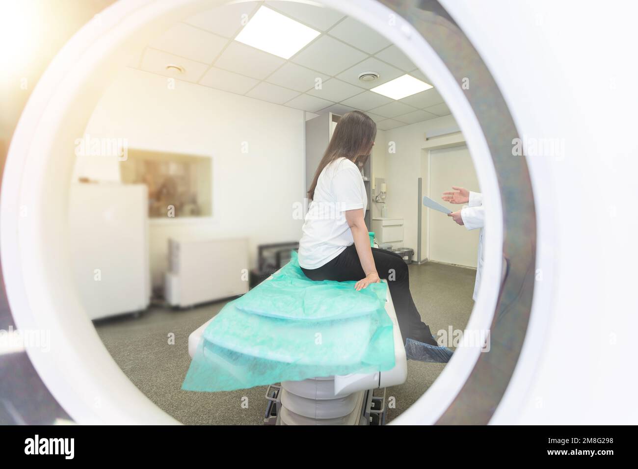 CT scan technologist overlooking patient in Computed Tomography scanner ...