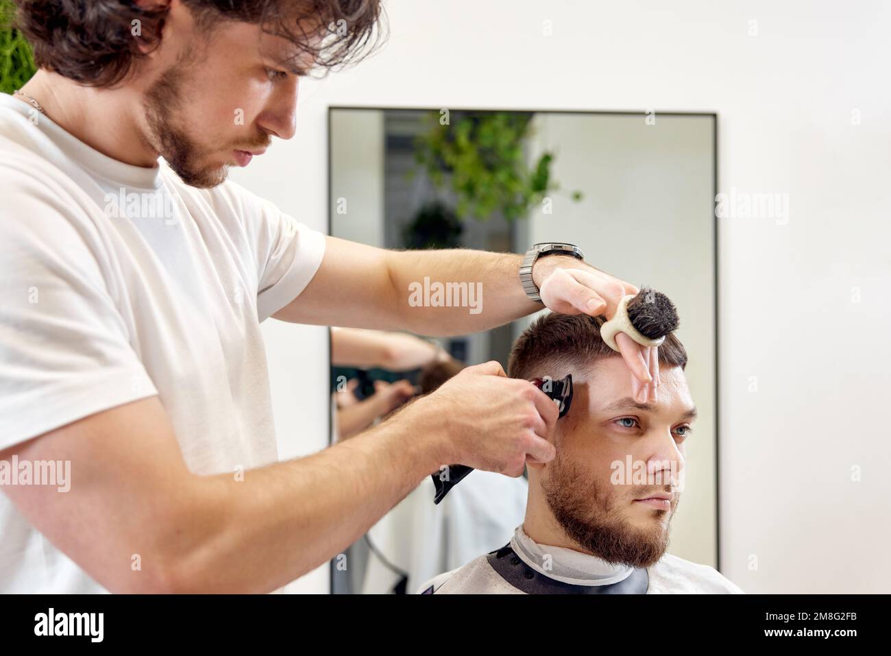 Barber trim hair with clipper on handsome bearded man Stock Photo - Alamy