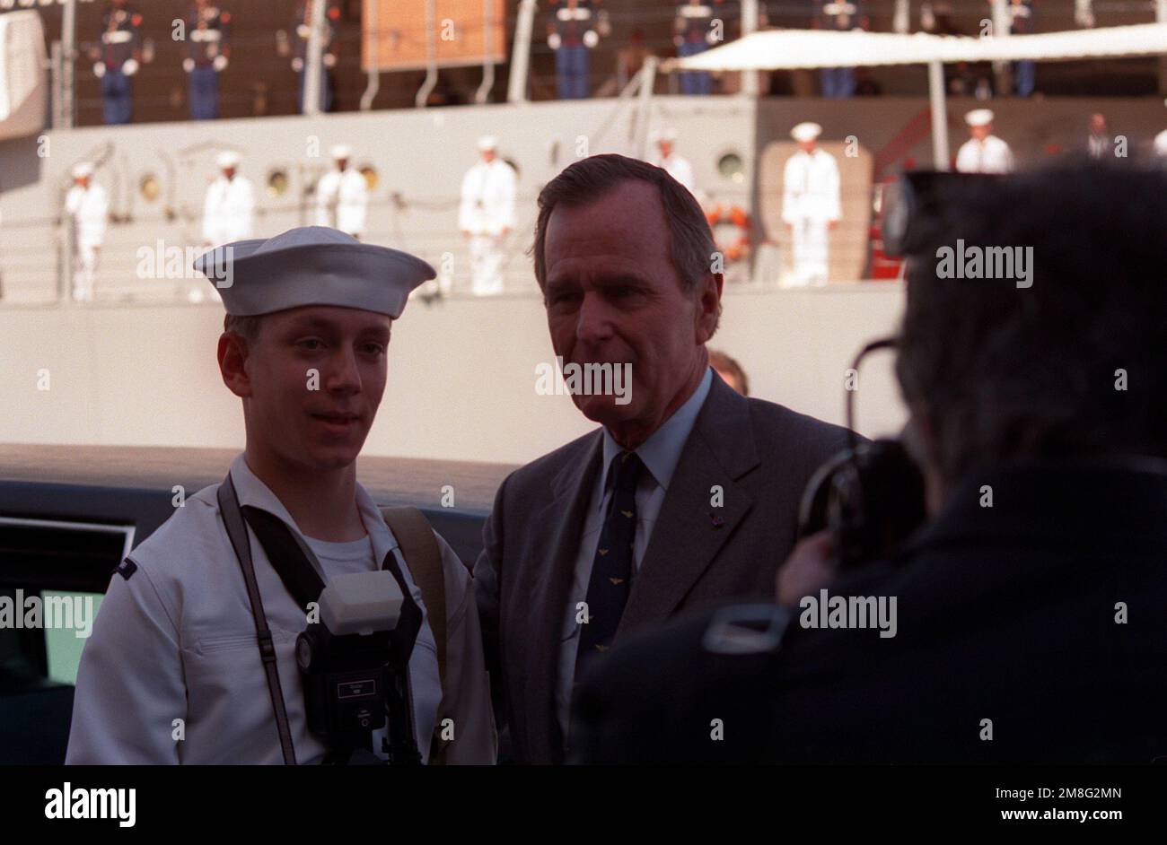 President George Bush poses for a photograph with a sailor during an ...