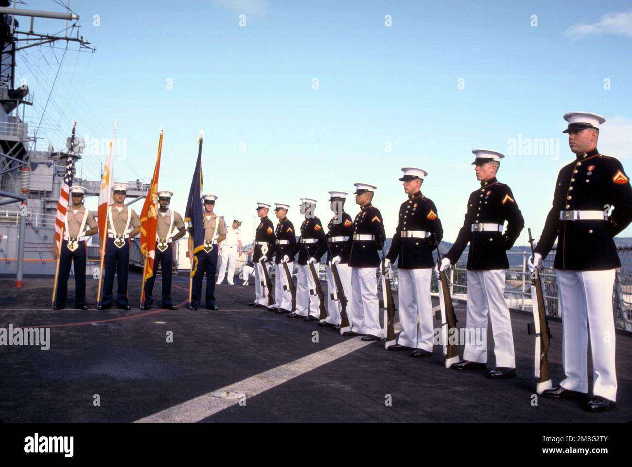 A Marine honor guard stands at parade rest beside the color guard ...