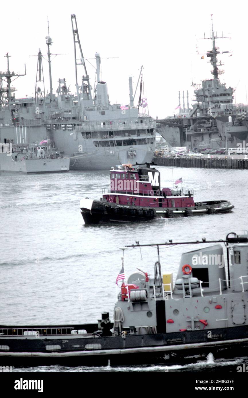 Tug boats pass by the destroyer ship USS STUMP (DD-978), left, the ...