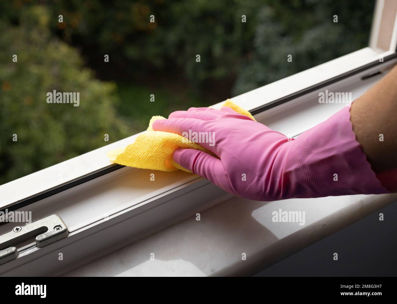 Hand holding a yellow microfiber cloth to clean dust on a window rail ...