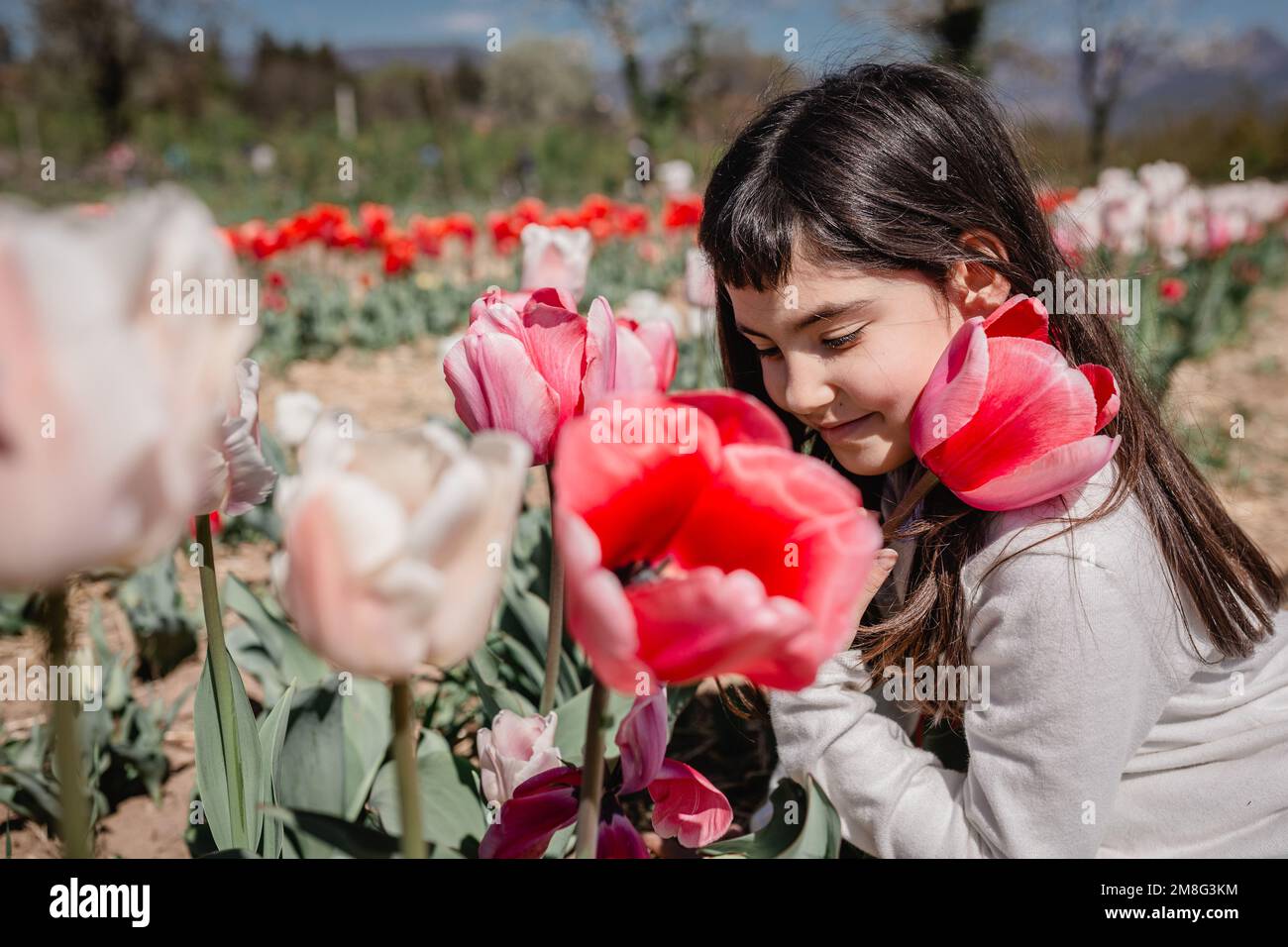 close up view of girl in white dress watching big flower sitting in ...