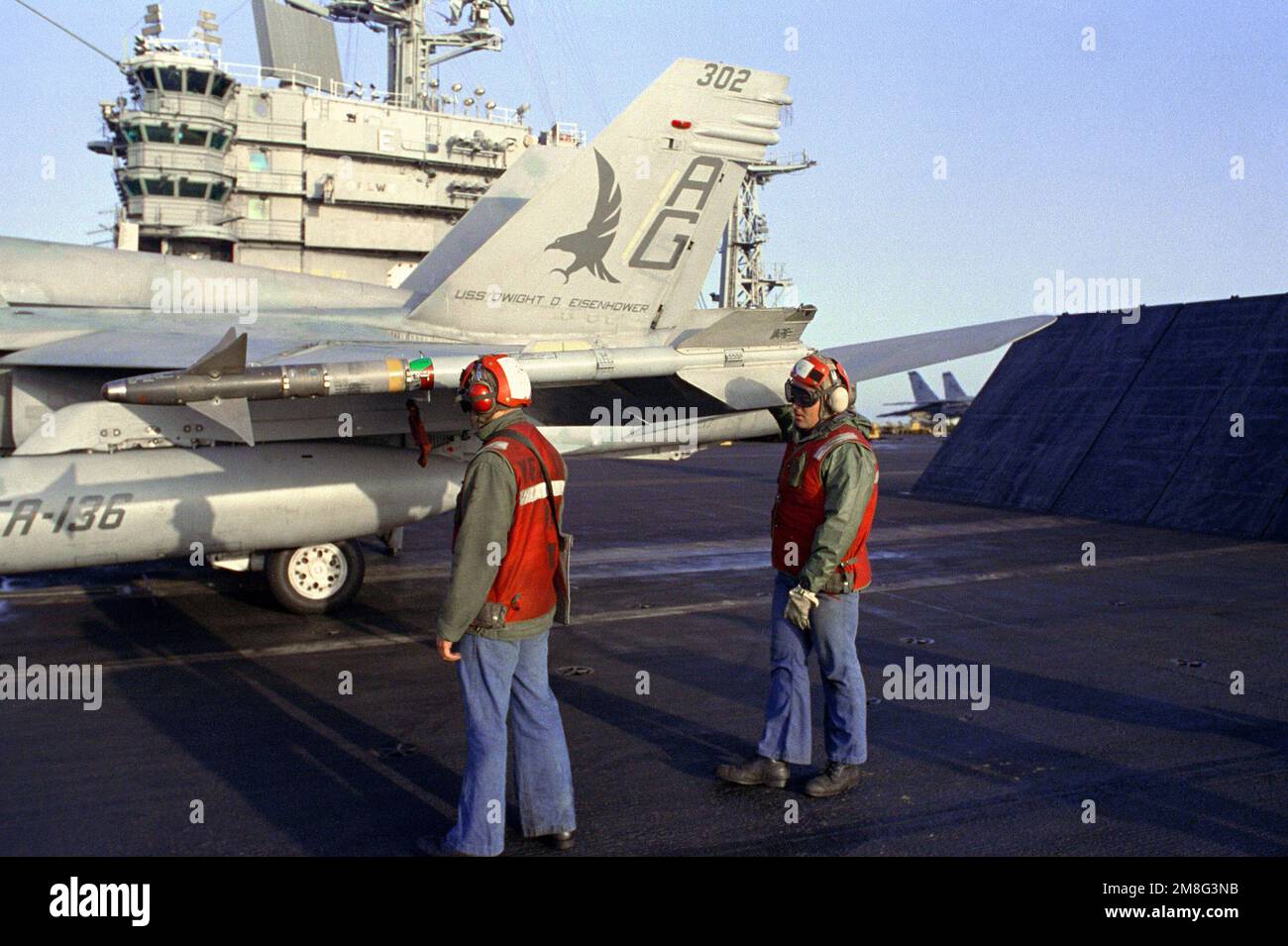 Flight deck crew members check an AIM-9 Sidewinder missile mounted on ...