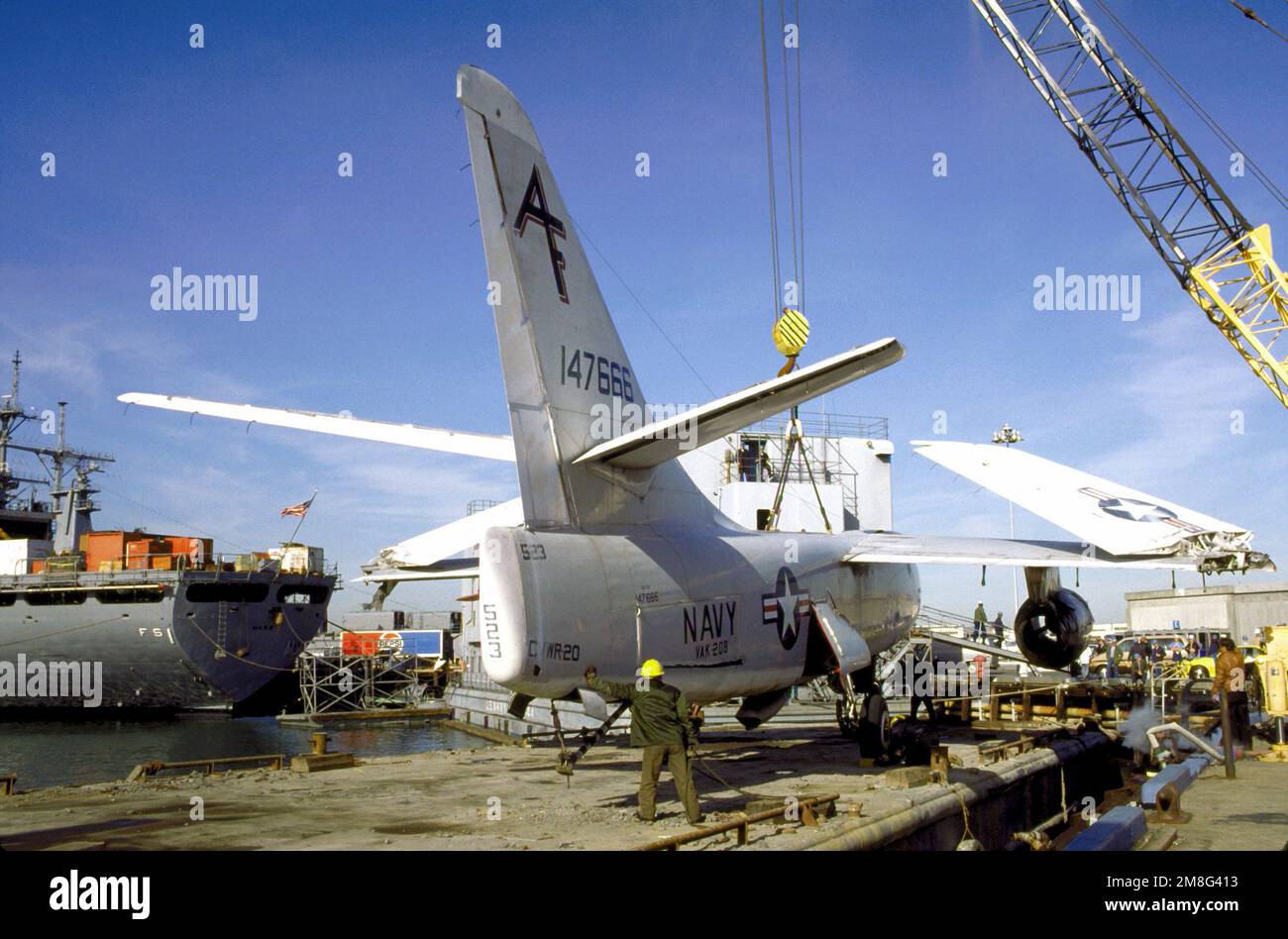 Workers use a crane to lift a Tactical Aerial Refueling Squadron 208 ...