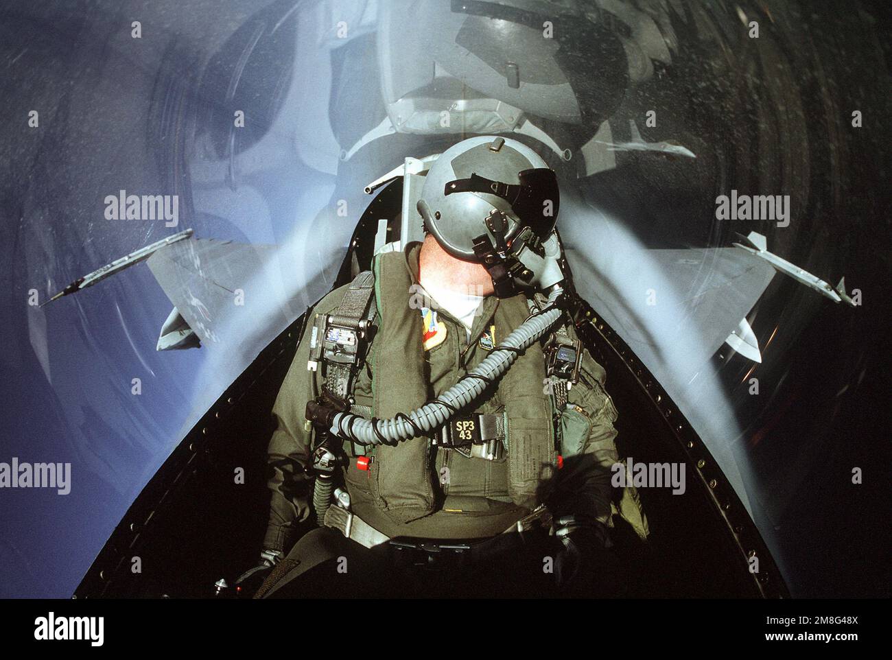 An F-16 fighter pilot turns to look for enemy aircraft while flying a ...