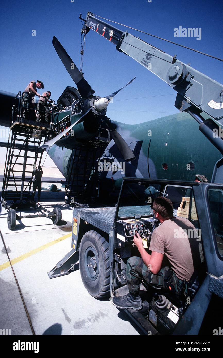 Ground crew members replace an engine on a C-130 Hercules aircraft ...