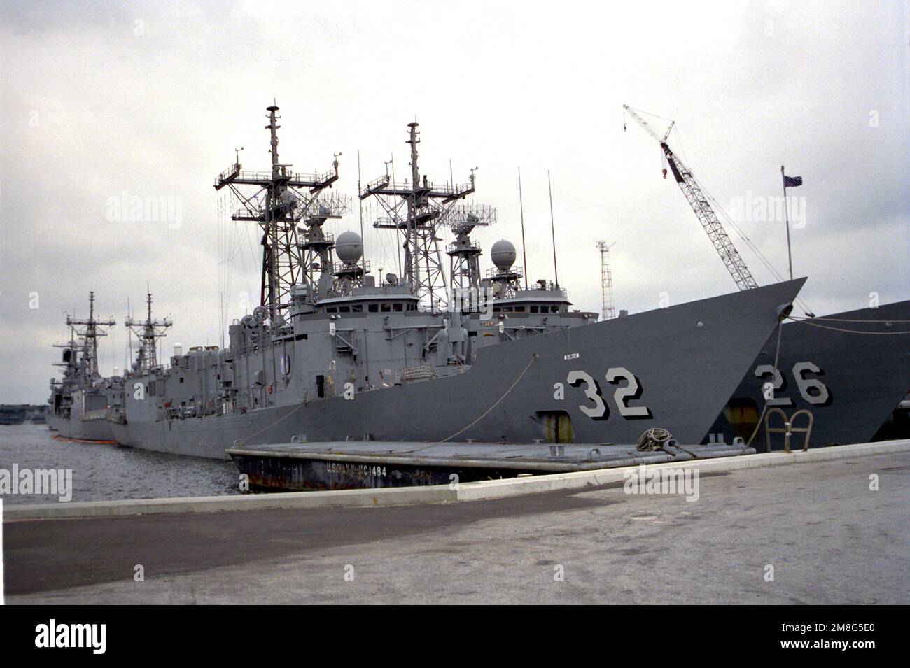 The guided missile frigate USS JOHN L. HALL (FFG-32), center, lies tied ...