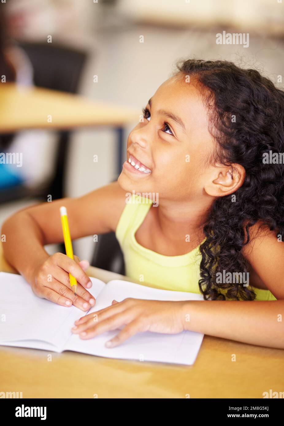 She loves learning. A cute little girl smiling as she does her homework ...