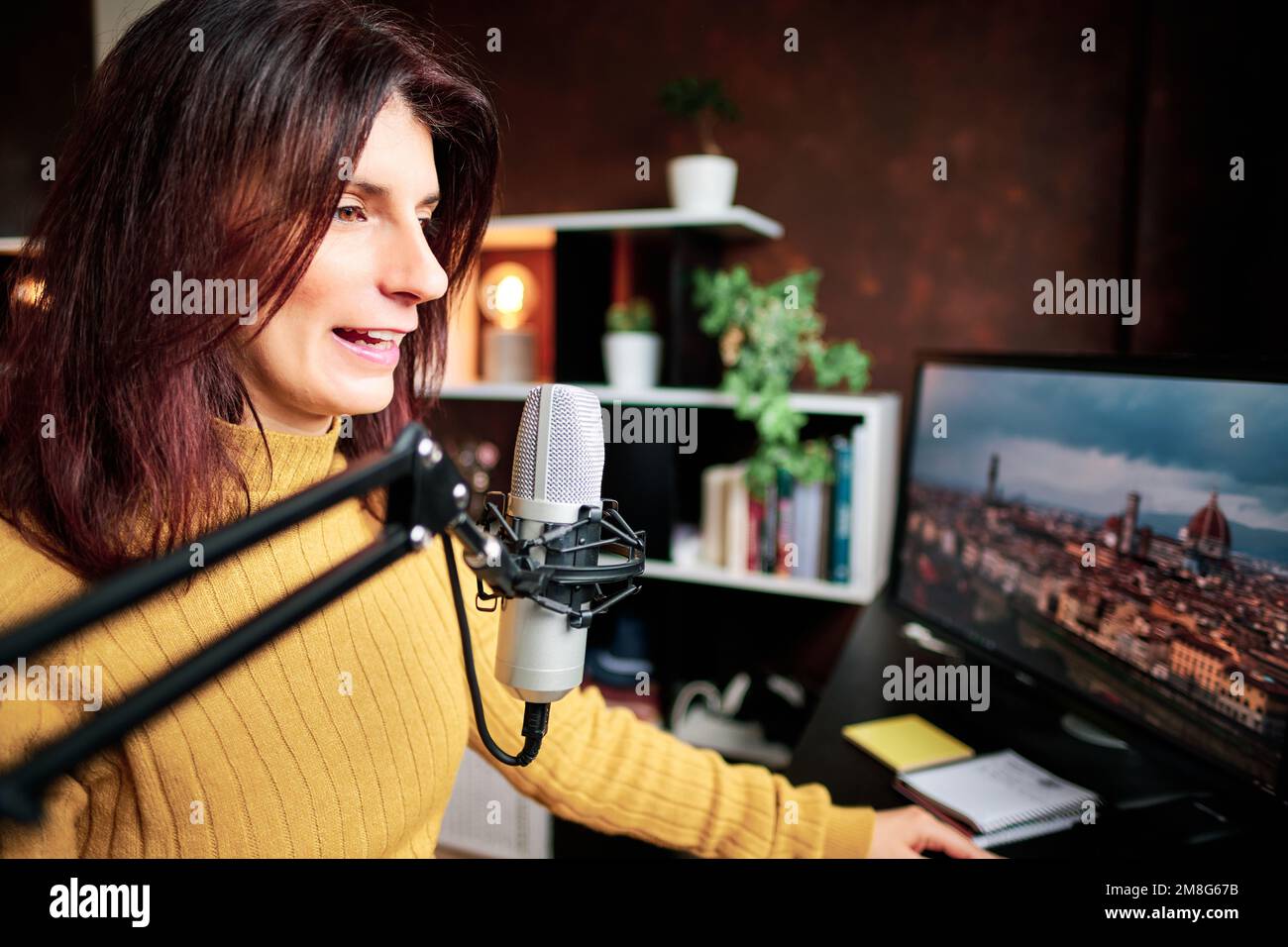 Woman recording podcast with microphone and computers from her homemade ...